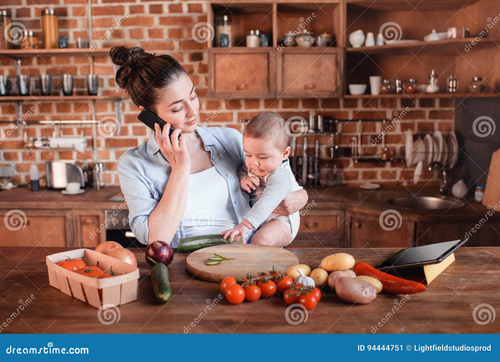 Mother with Son Talking on Smartphone and Preparing Dinner in the ...