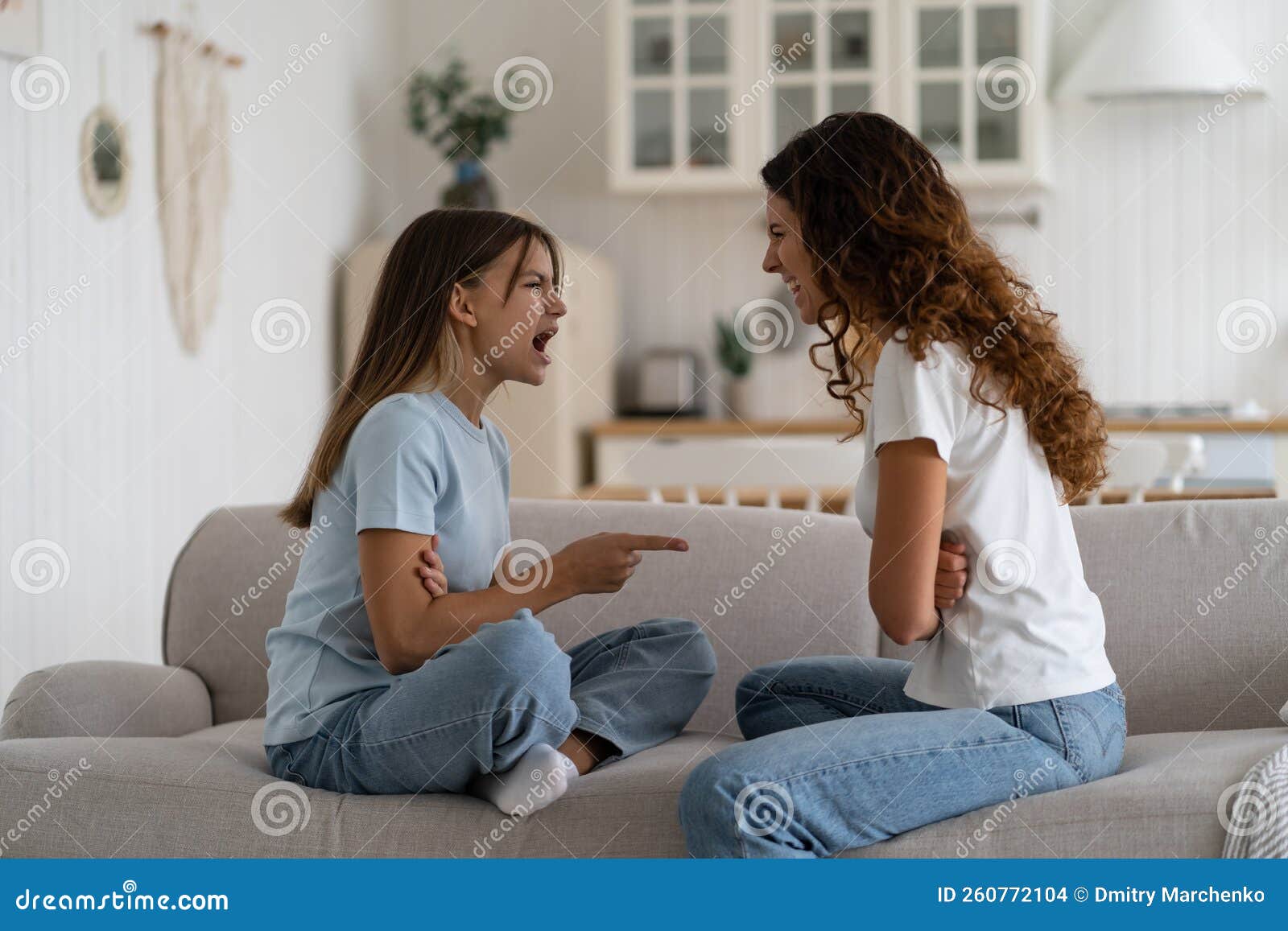Mother And Teen Daughter Arguing While Sitting In Front Of Each Other
