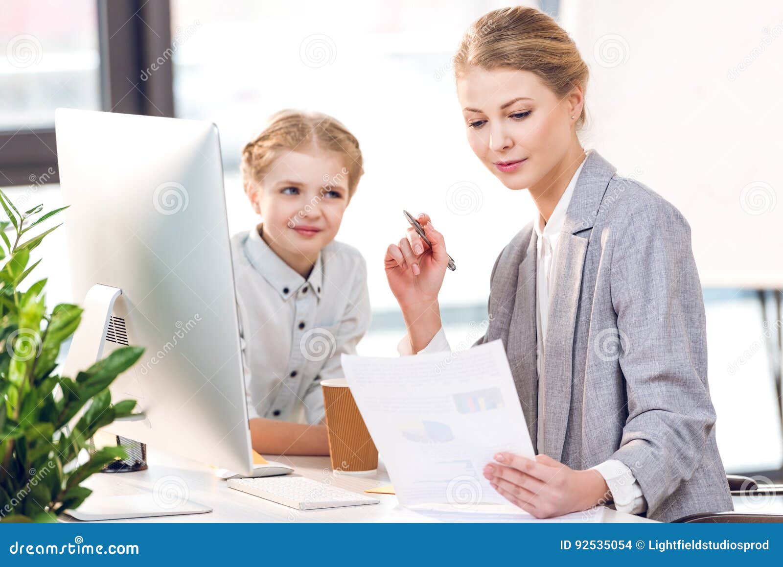 Mother Working with Computer and Documents while Daughter Looking on ...