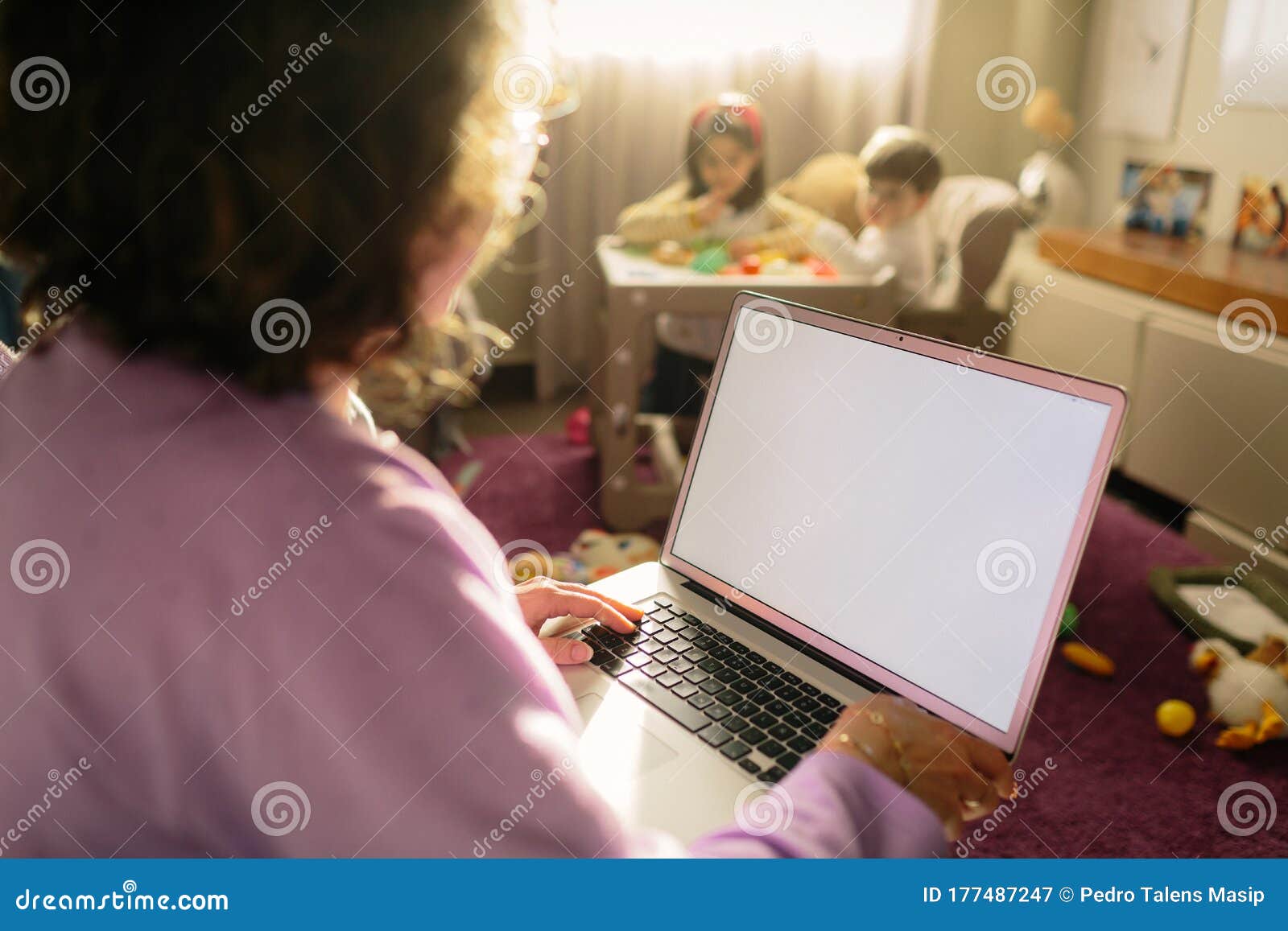 Mother Working on the Sofa with the Laptop while the Children are ...