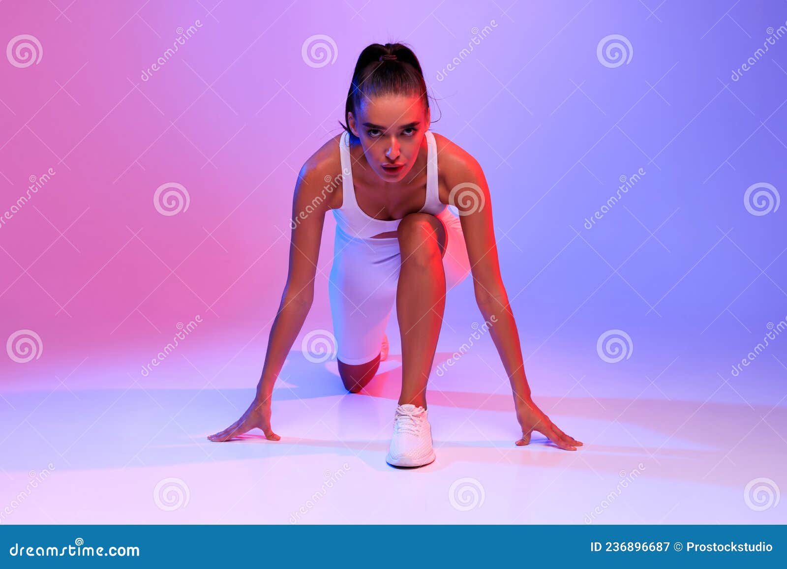 Motivated Female Runner Doing Crouch Start on Neon Background, Front ...