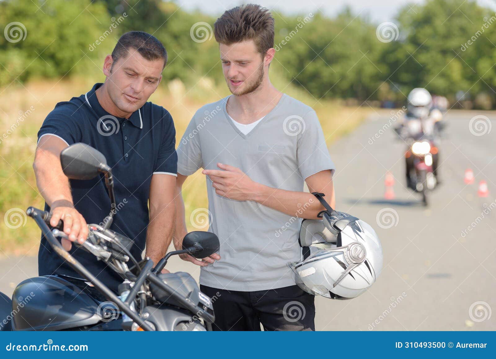 Motorcycle Driving Instructor Explaining Handlebar Controls To Young ...
