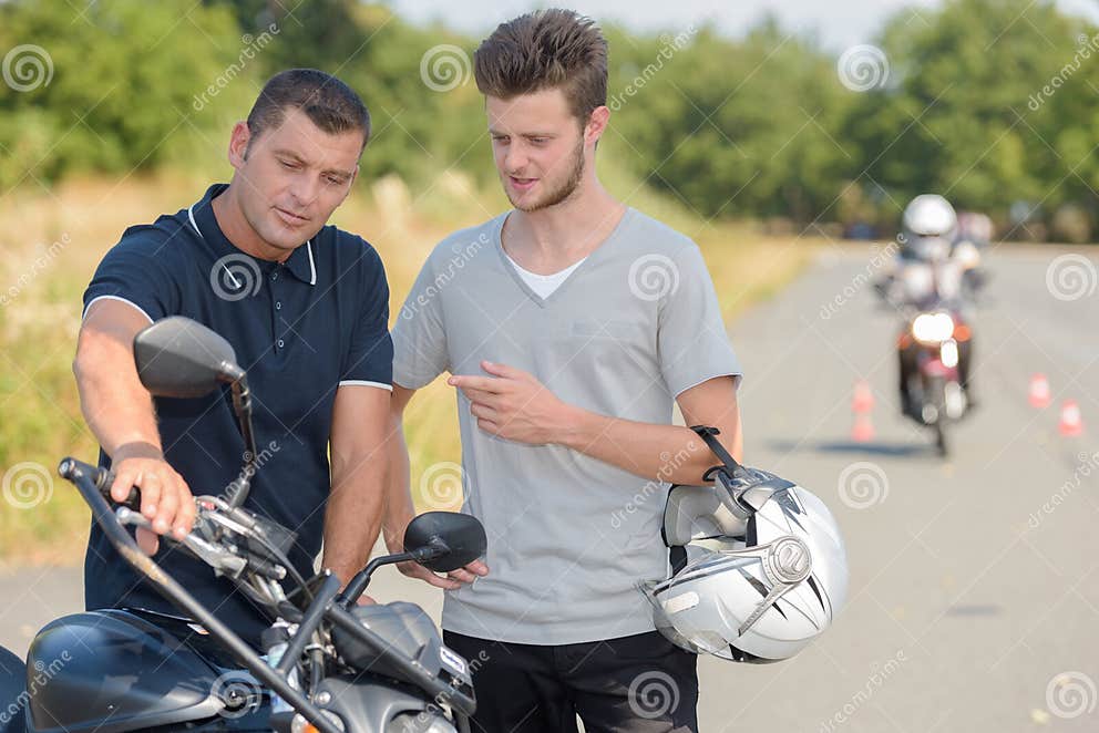 Motorcycle Driving Instructor Explaining Handlebar Controls To Young ...