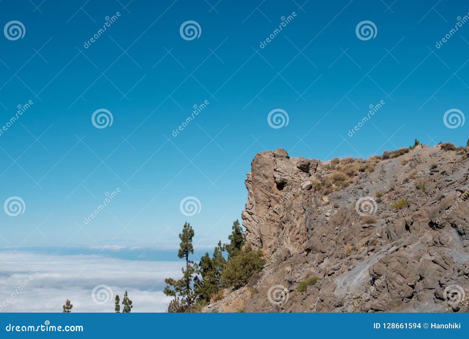 Mountain Cliff Above Clouds with Clear Blue Sky Background - Stock ...