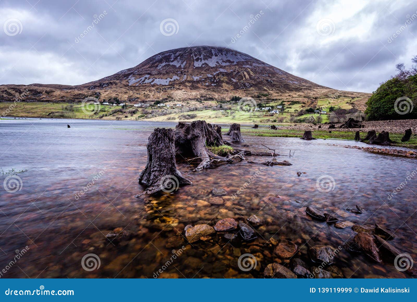Single High Mountain with Pick in Clouds and Tree Trunks in Lake in ...