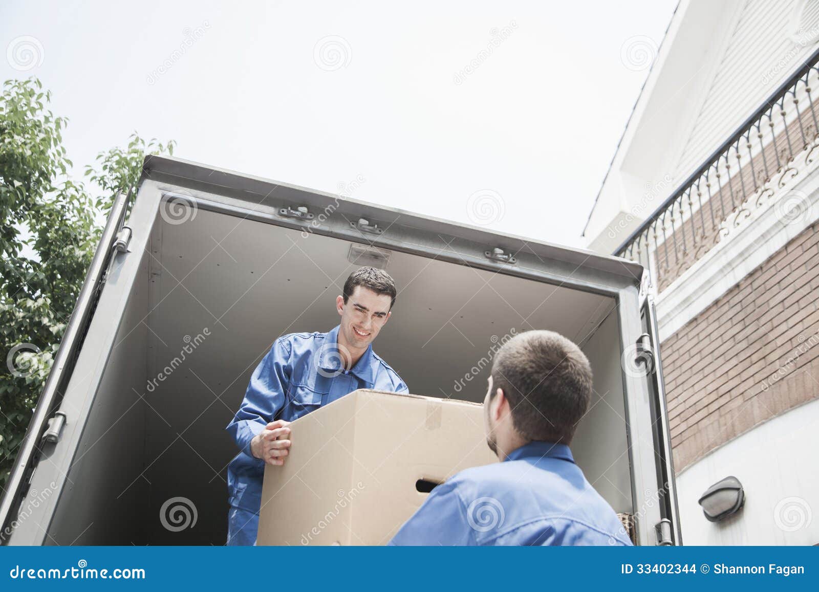 Movers Unloading a Moving Van, Passing a Cardboard Box Stock Photo ...