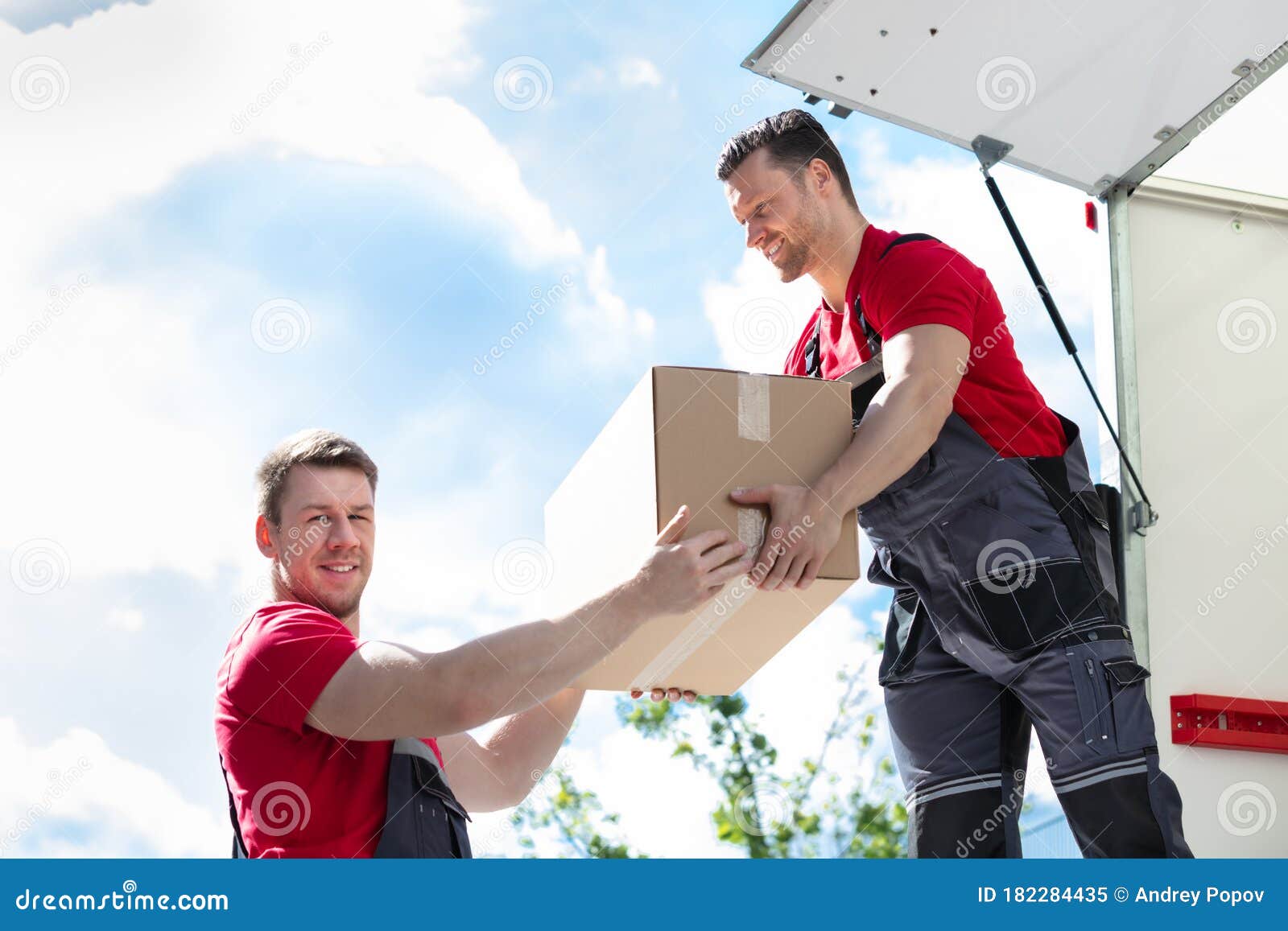 Movers Unloading a Moving Van and Passing a Cardboard Box Stock Image ...