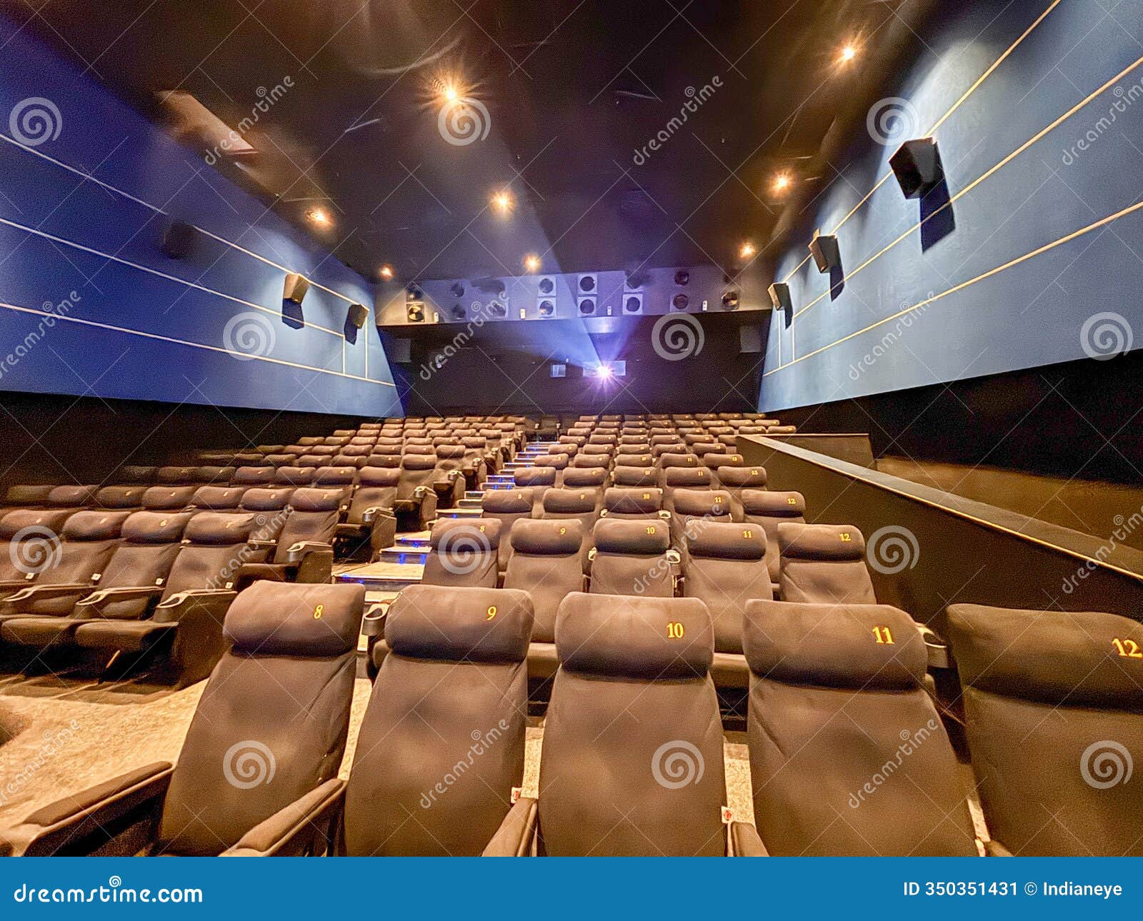 A Movie Theater with Rows of Chairs and a Projector Screen Stock Image ...