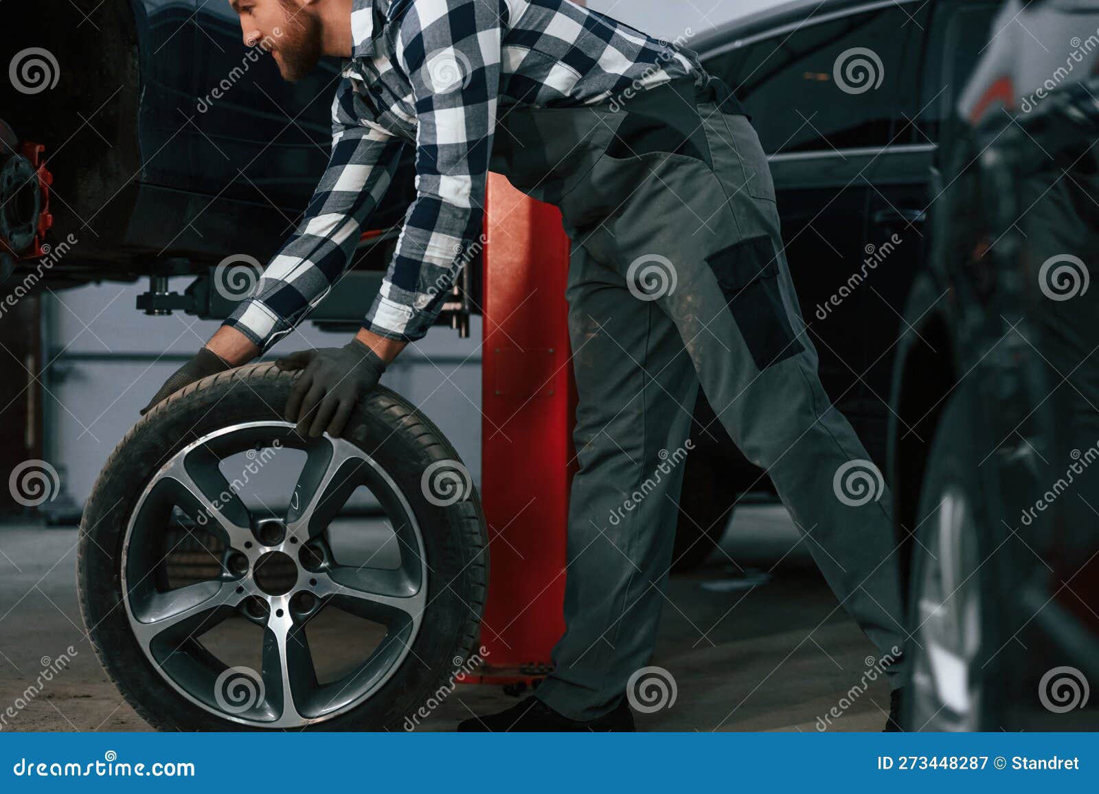 Moving the New Tire for a Car. Man in Uniform is Working in the Auto ...
