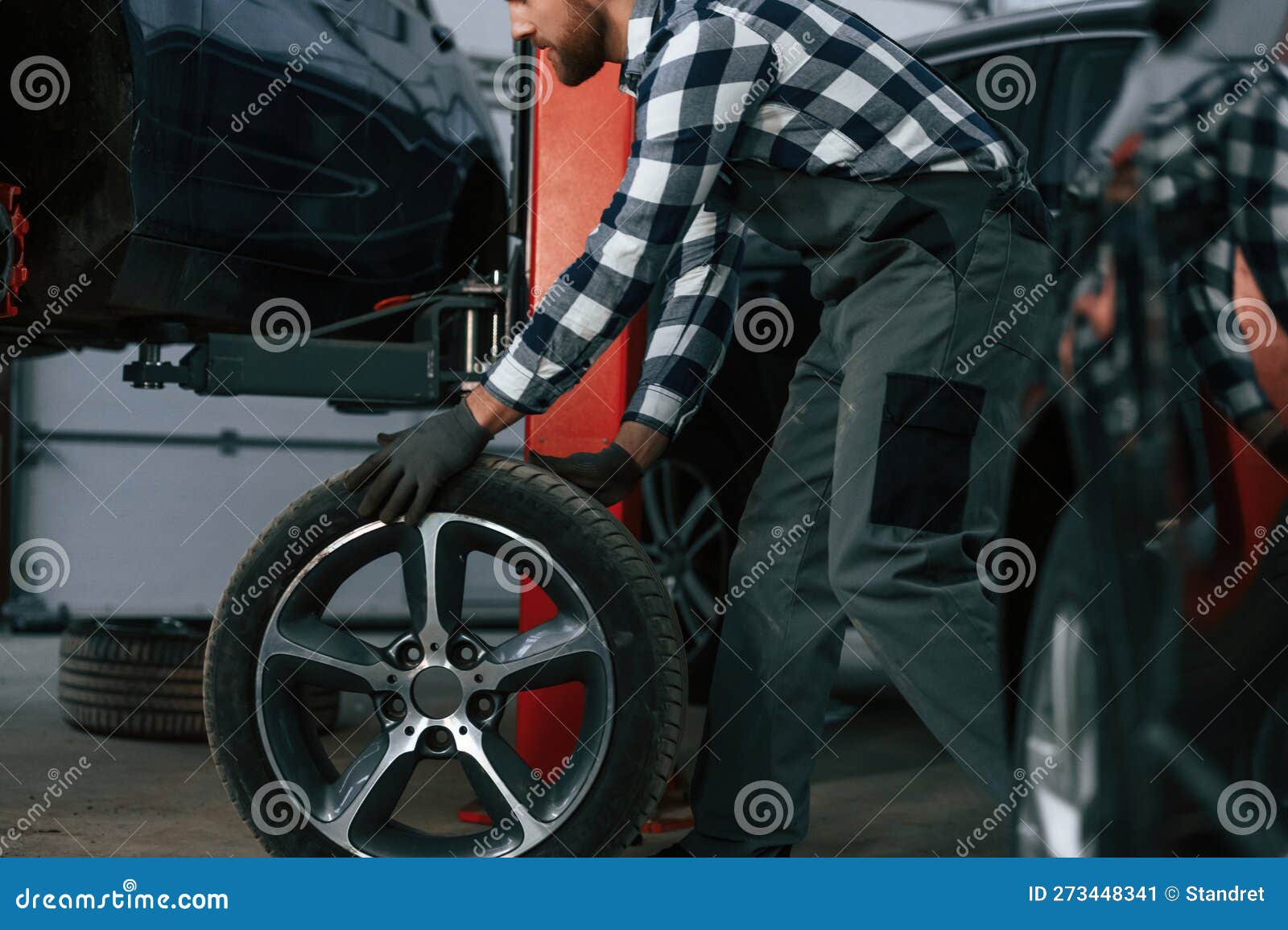 Moving the New Tire for a Car. Man in Uniform is Working in the Auto ...