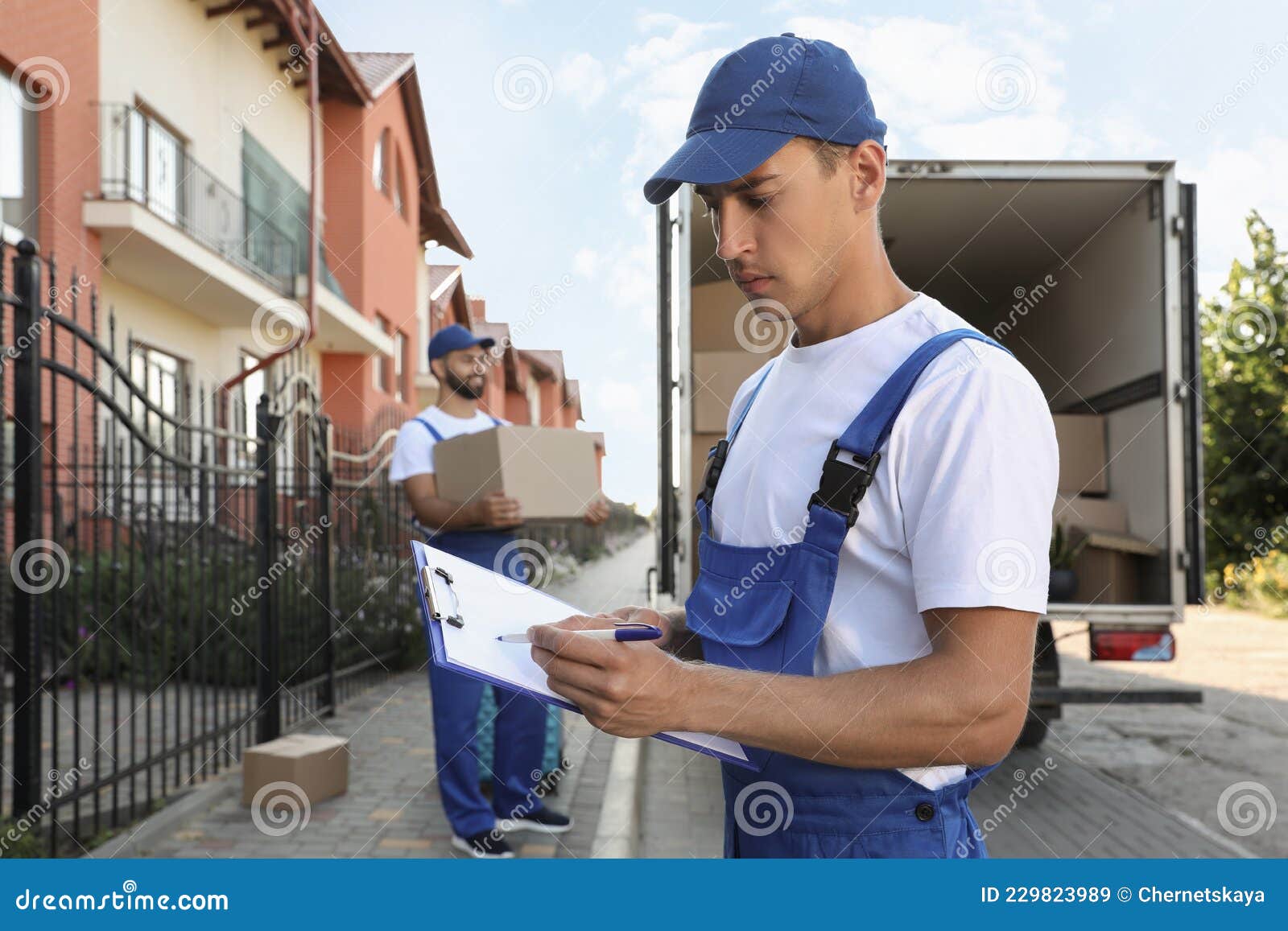 Moving Service Workers Outdoors, Unloading Boxes and Checking List ...