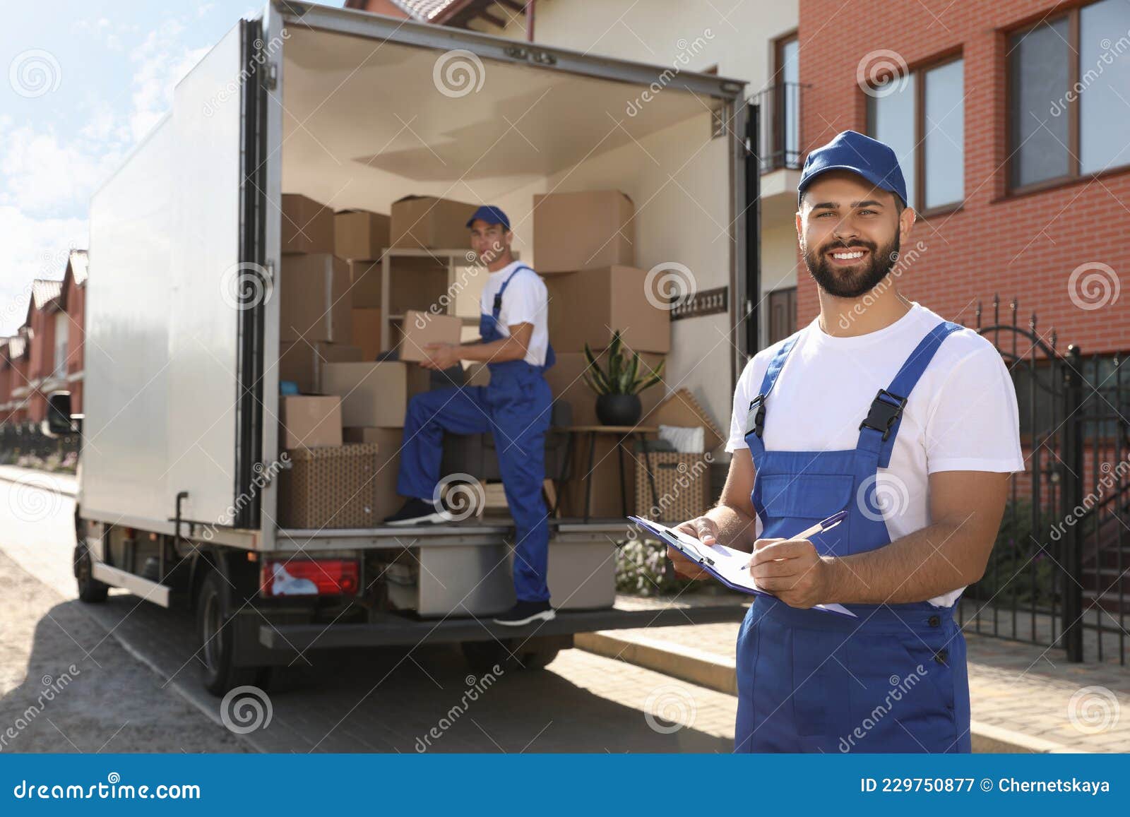 Moving Service Workers Outdoors, Unloading Boxes and Checking List ...