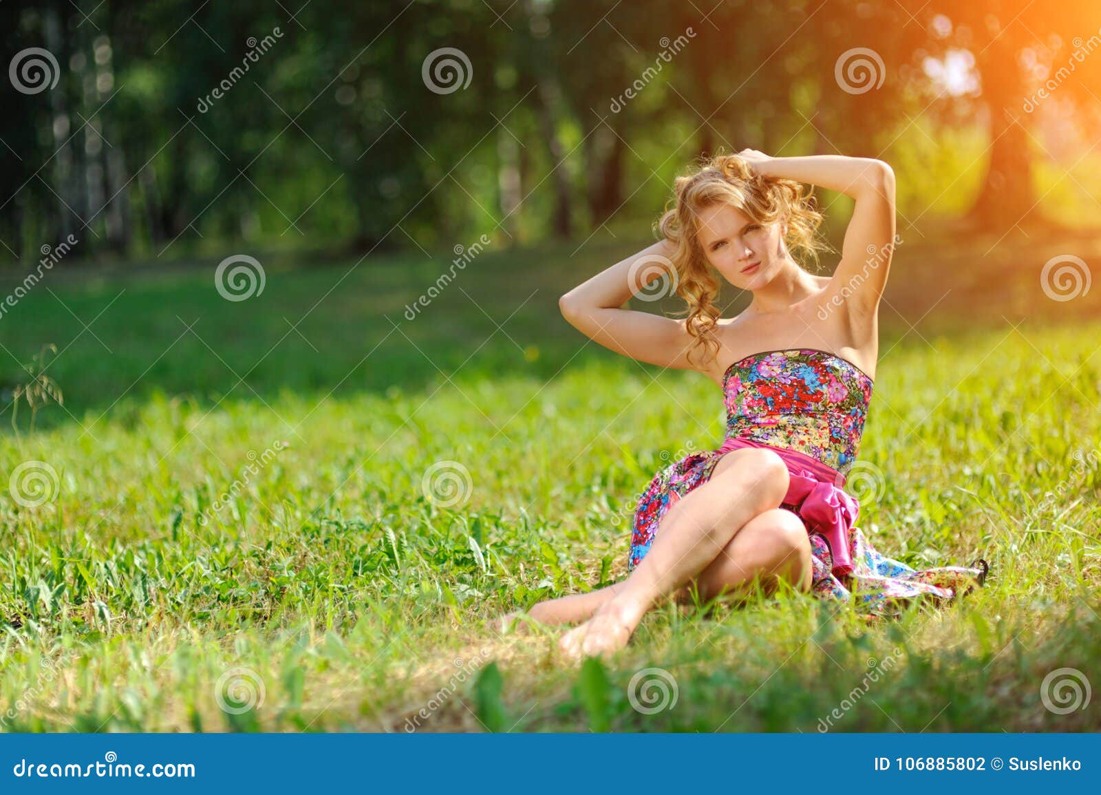 Muchacha Rubia Joven En El Vestido Colorido Brillante Que Plantea La Mentira En Hierba En Parque