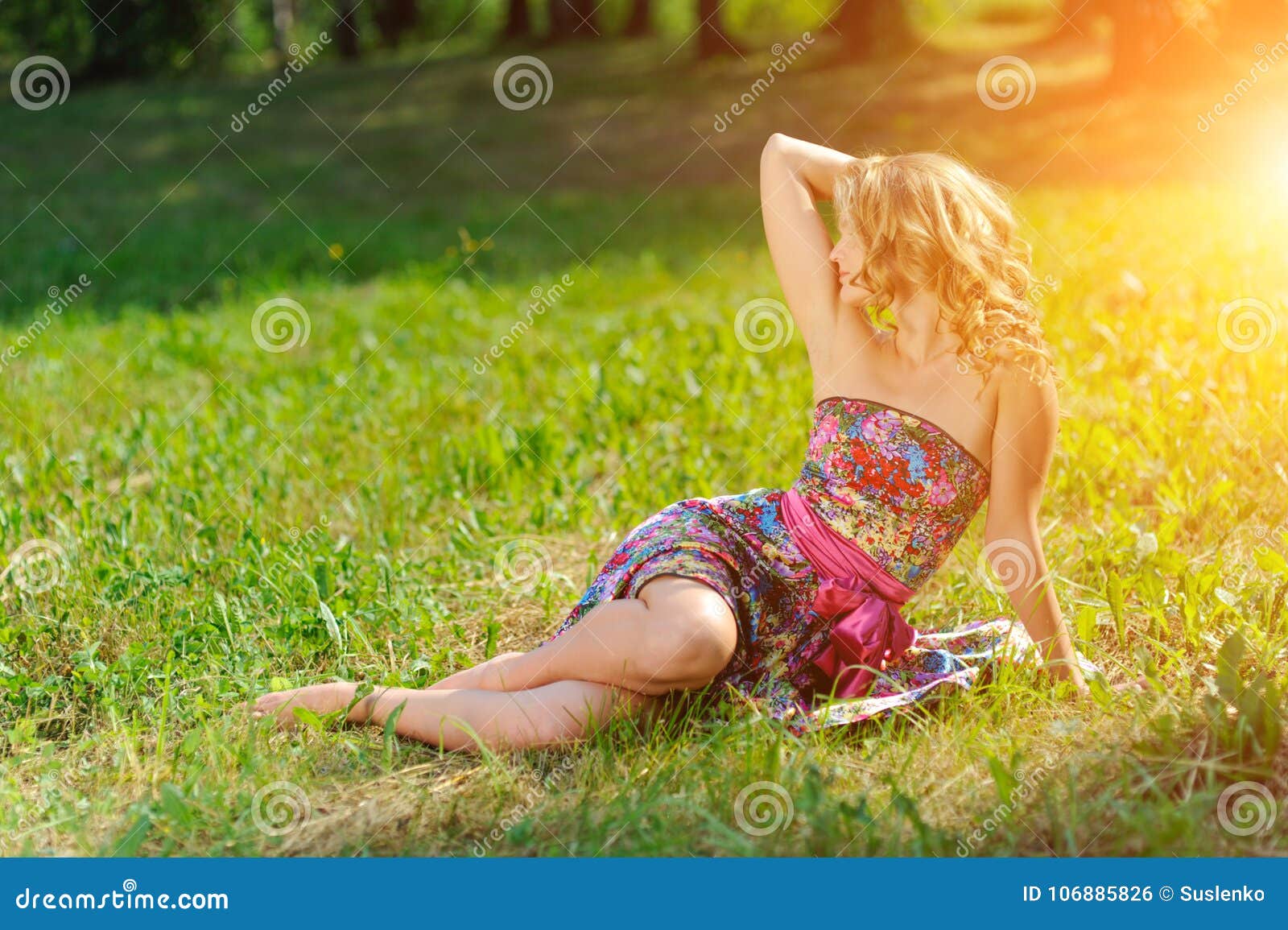 Muchacha Rubia Joven En El Vestido Colorido Brillante Que Plantea La Mentira En Hierba En Parque