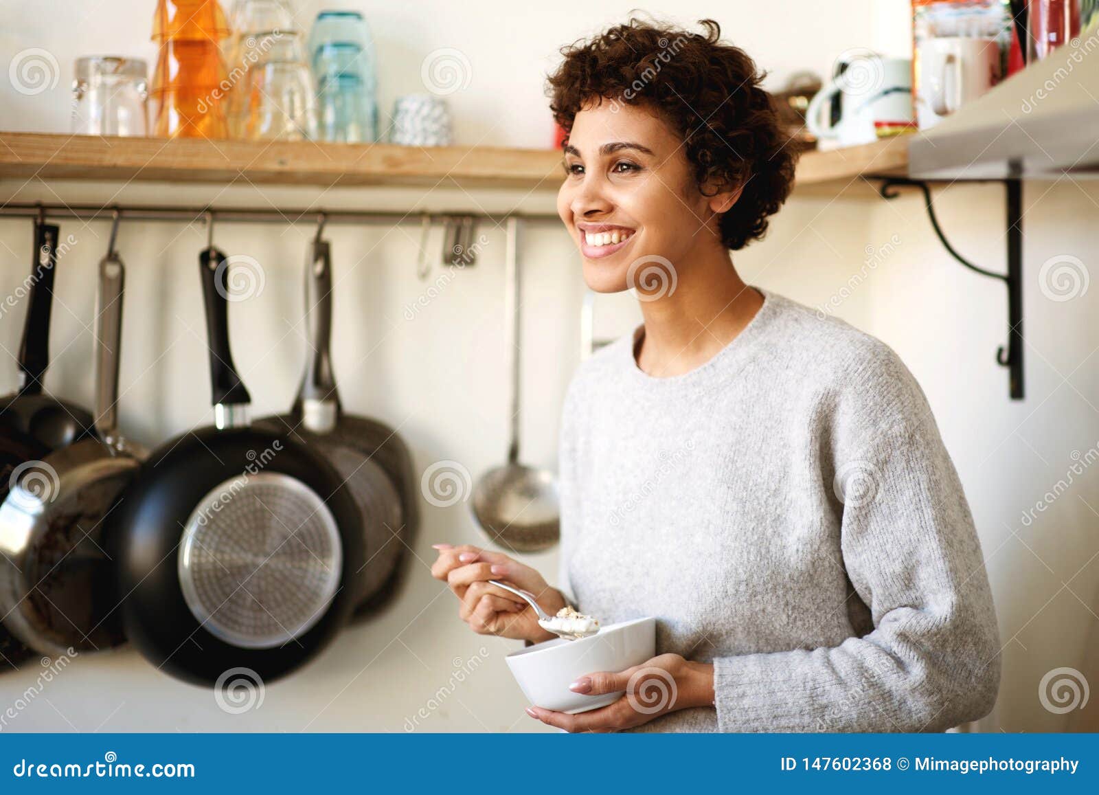 Mujer Afroamericana Sonriente Parada En La Cocina Comiendo Cereales ... Mujer Afroamericana Sonriente Parada En La Cocina Comiendo Cereales ...