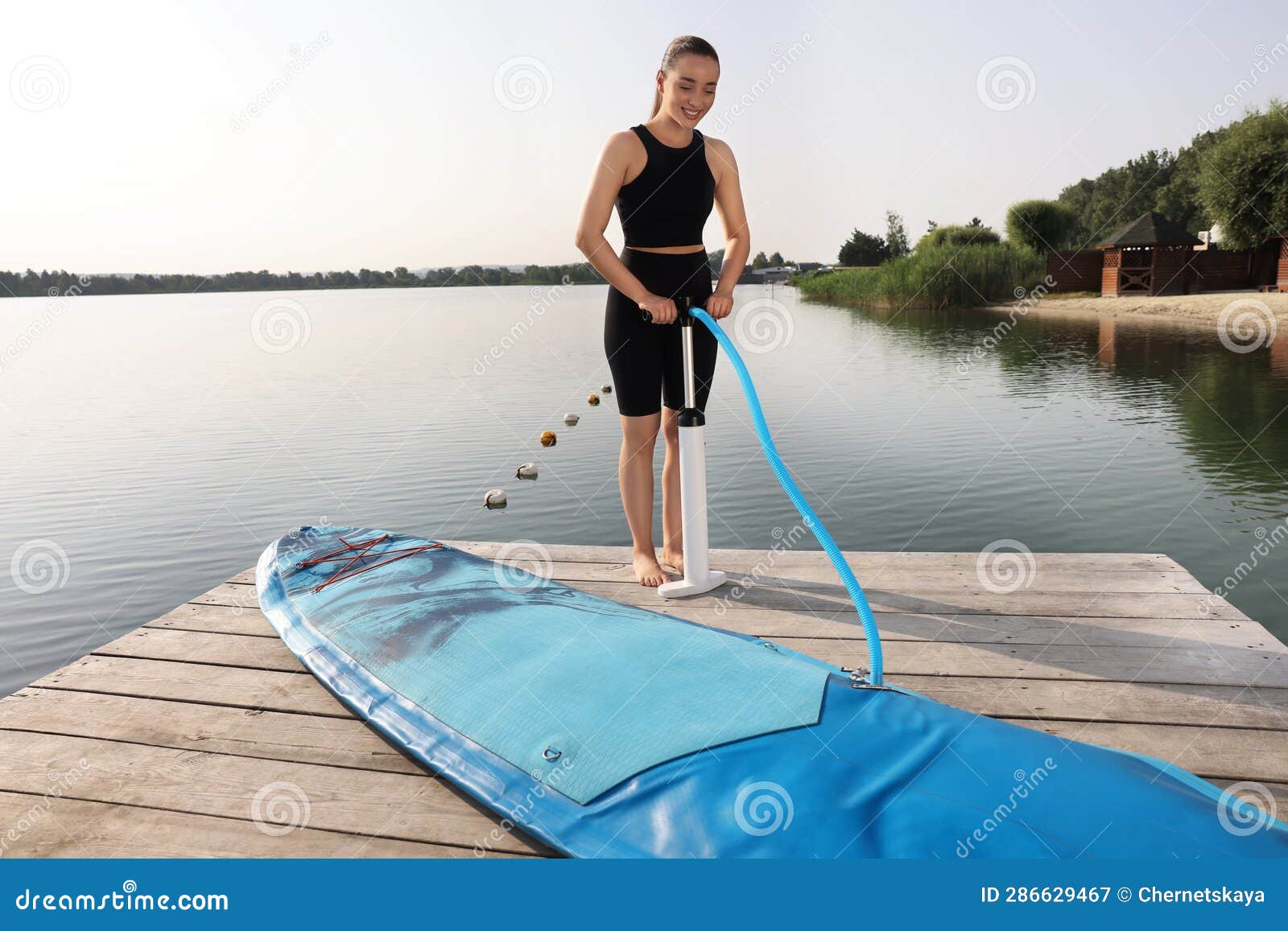 Mujer Bombeando La Tabla De Sup En El Muelle Imagen de archivo - Imagen ...