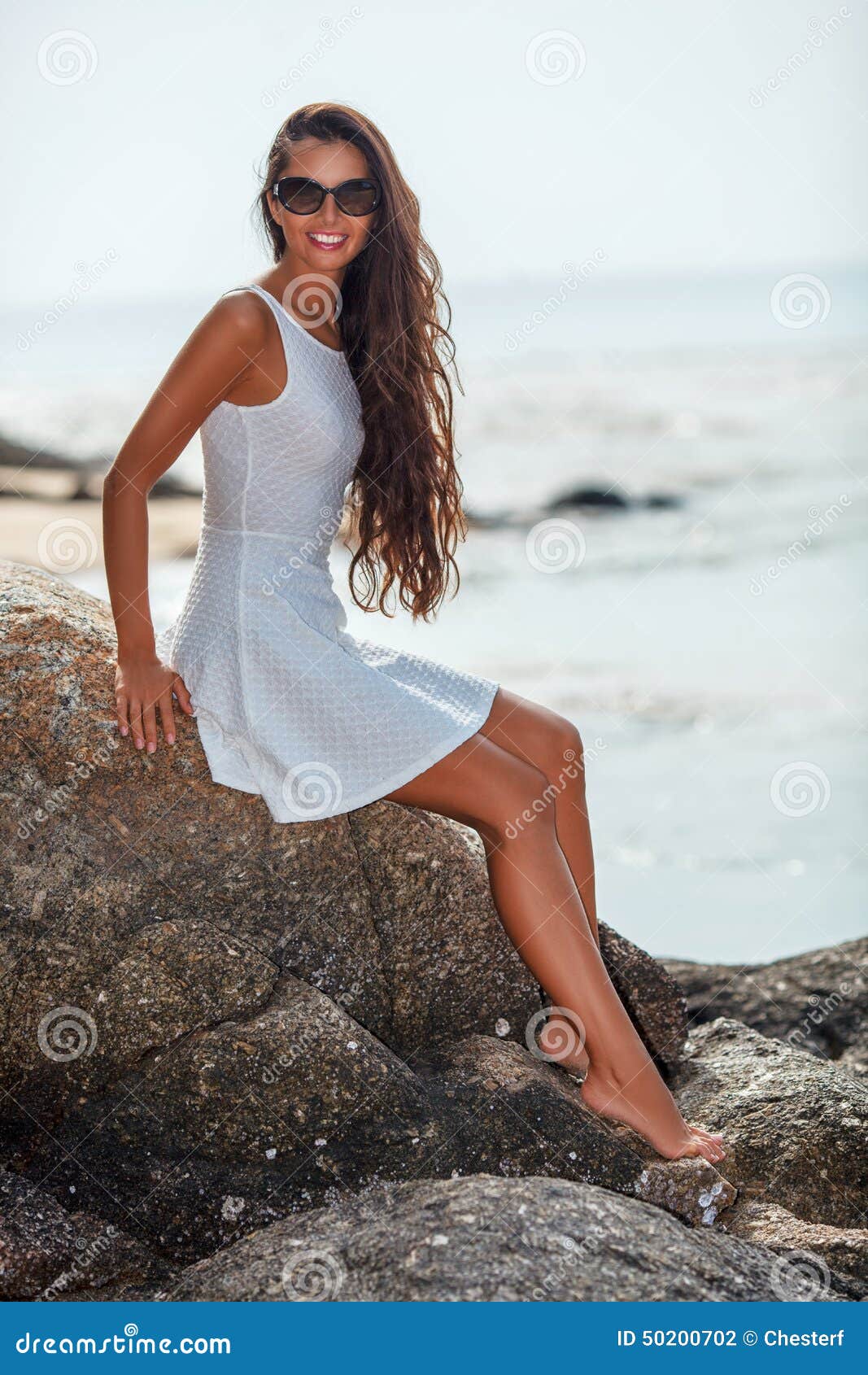 Mujer Bronceada Hermosa Que Se Sienta En Piedra Foto de archivo ...