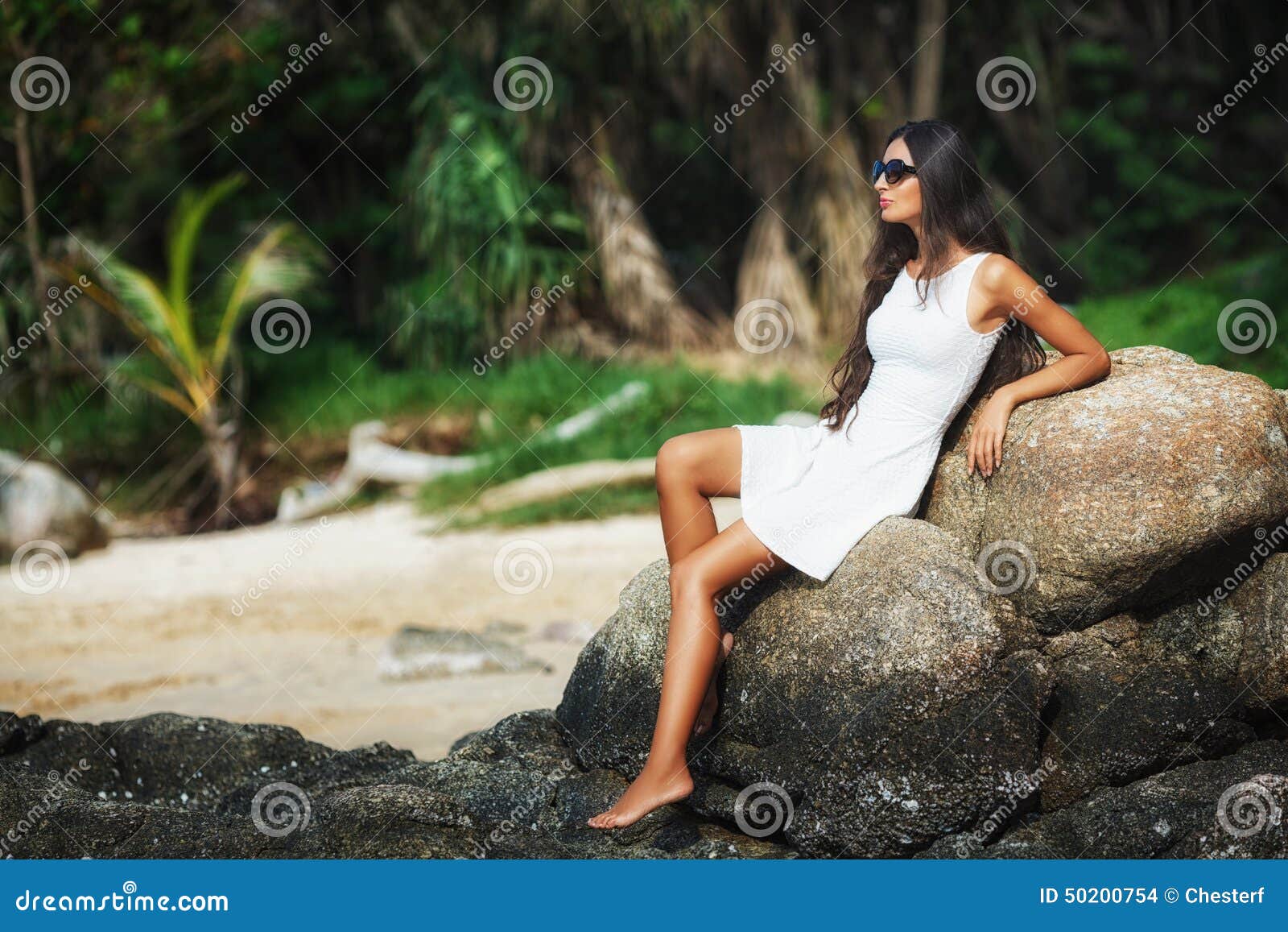 Mujer Bronceada Hermosa Que Se Sienta En Piedra Foto de archivo ...