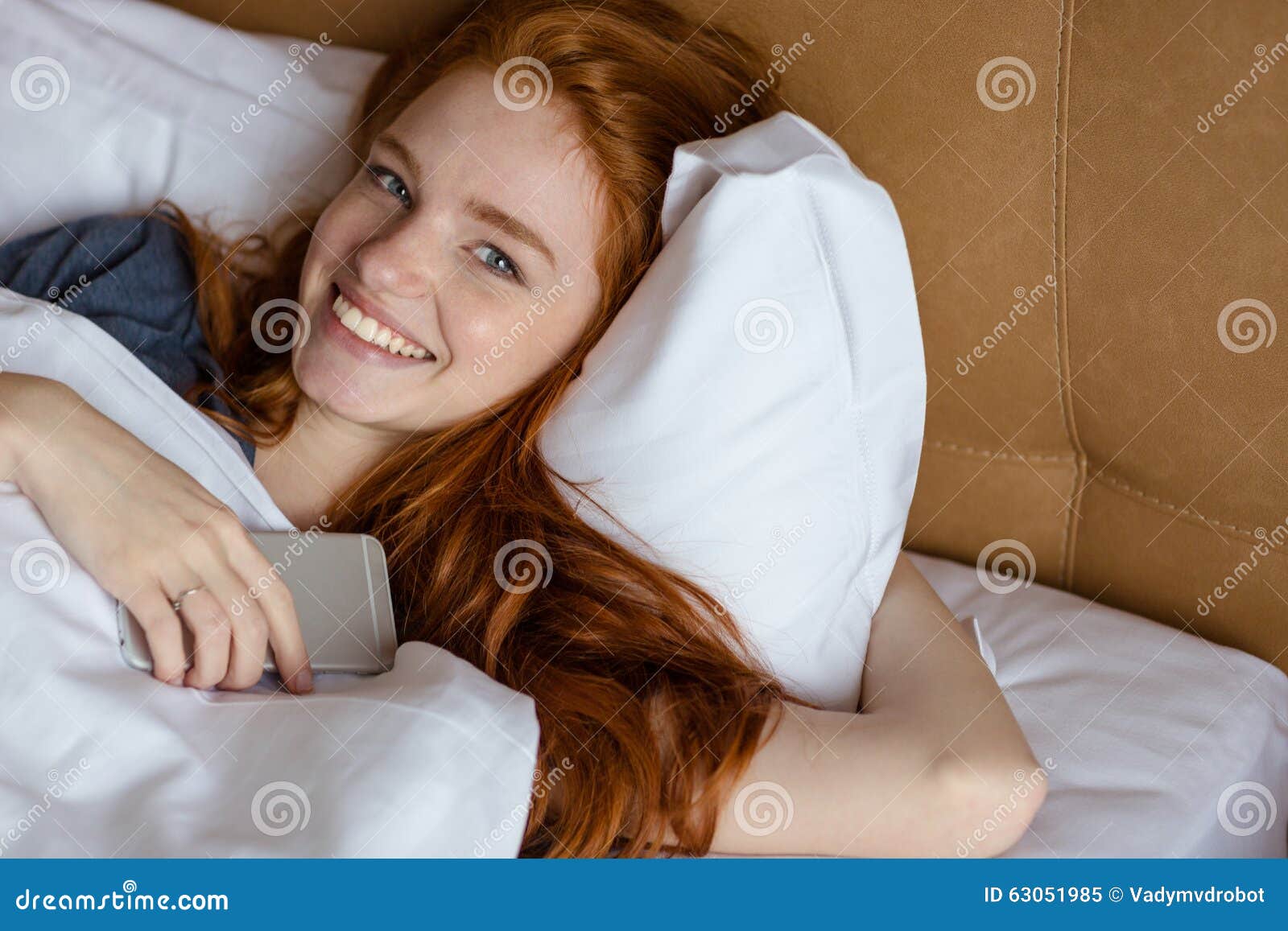 Mujer Del Pelirrojo Que Miente En La Cama Con Smartphone Imagen De