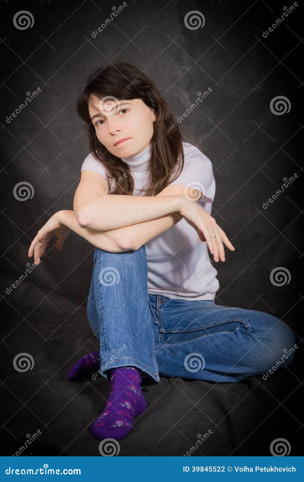 Mujer En Los Vaqueros Que Se Sientan En El Piso Foto de archivo ...