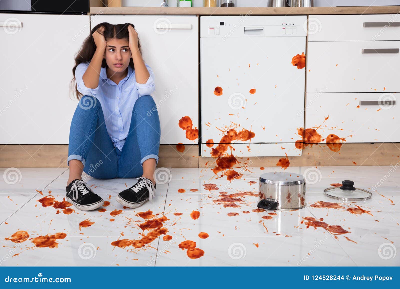Mujer Que Se Sienta En Piso De La Cocina Con La Comida Derramada Foto ...