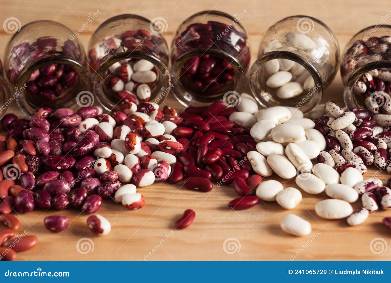 Multi-colored Beans are Poured Out of Jars on the Table. White, Red and ...