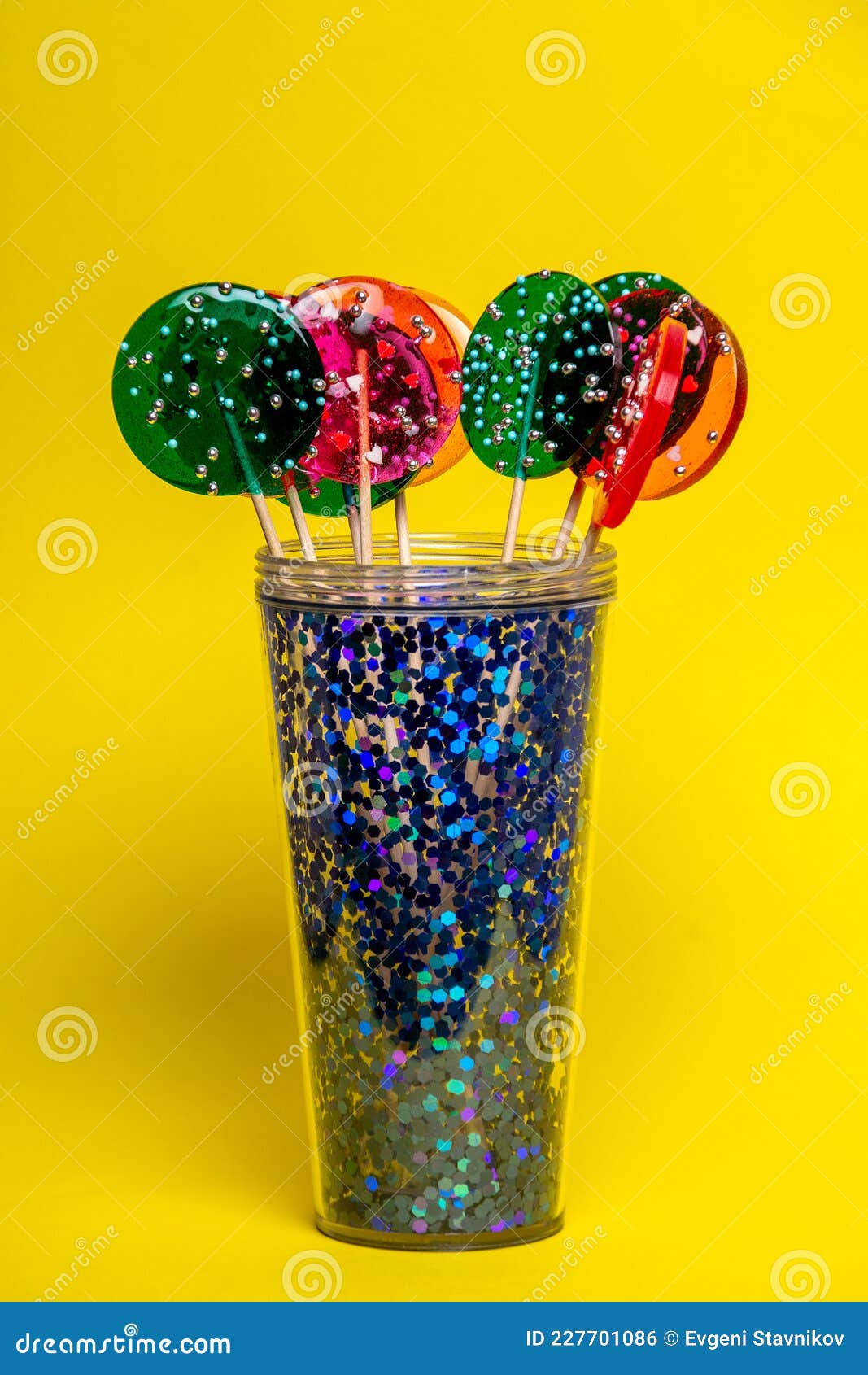 Multi-colored Lollipops in a Blue Glass on a Yellow Background. Stock ...