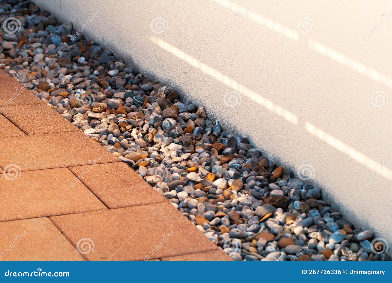 Multi-colored Smooth Pebbles As Drainage at the Base of a White ...