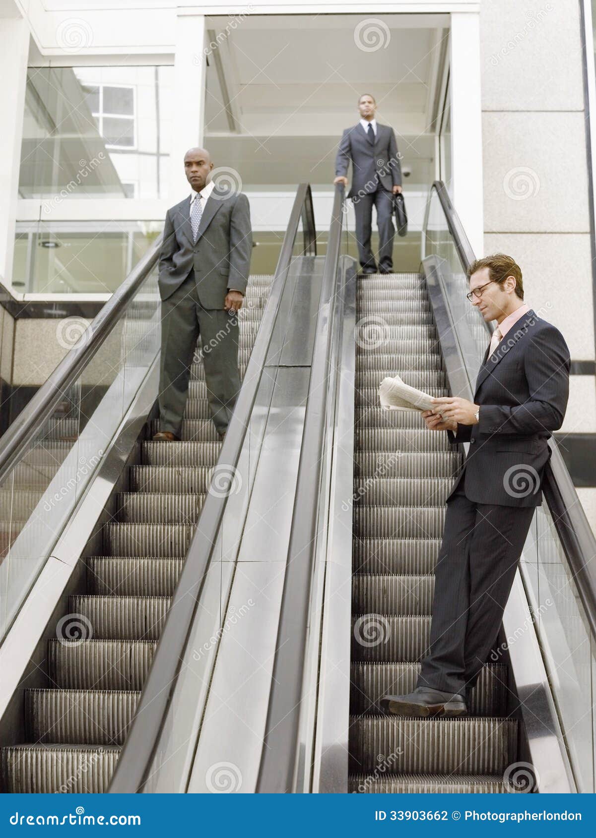 Multi Ethnic Businessmen Standing on Escalator in Office Stock Photo ...