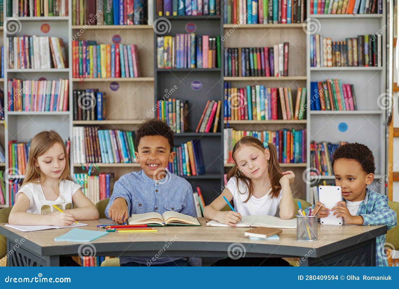 Multi-ethnic Pupils Study and Write at Table in Library or Classroom ...