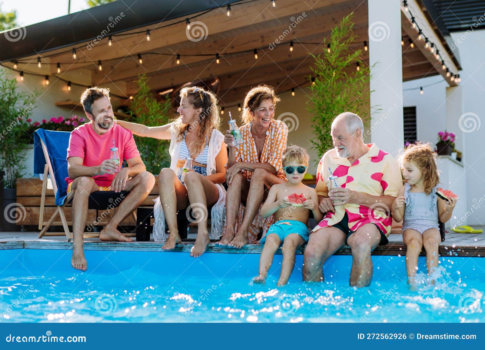 Multi Generation Family Enjoying Summer Time, Sitting at Backyard Pool ...