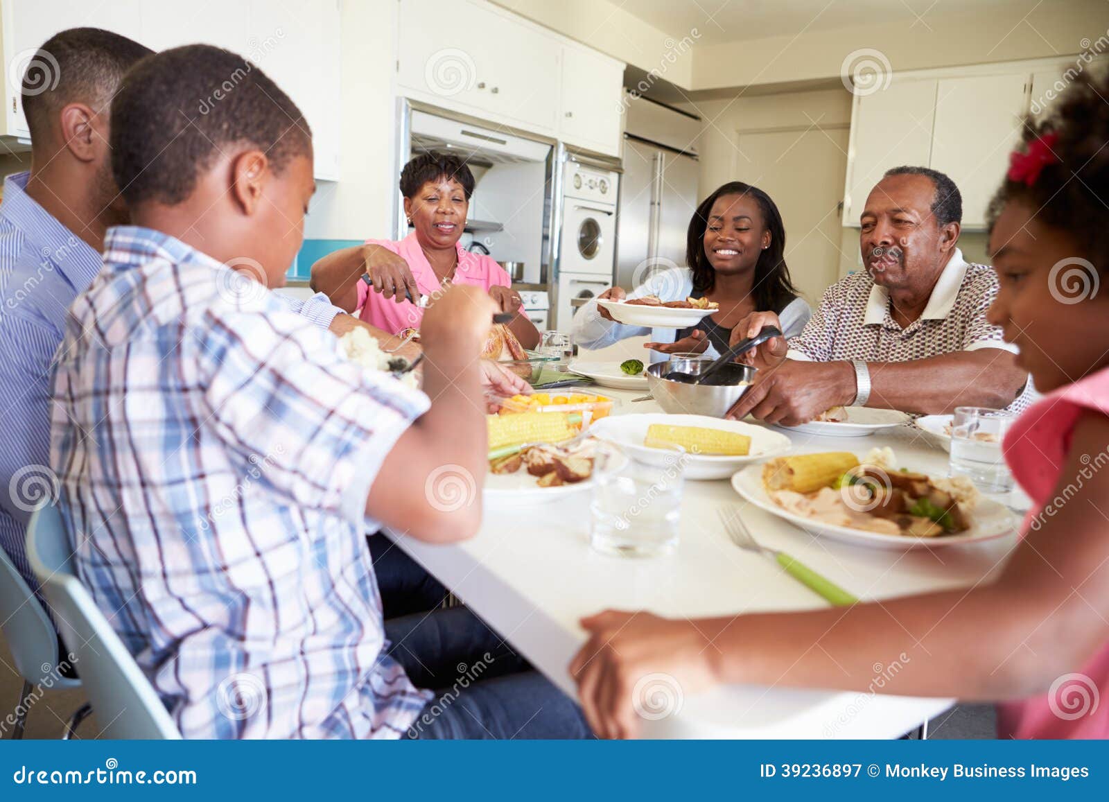 Multi-Generation Family Sitting Around Table Eating Meal Stock Image ...