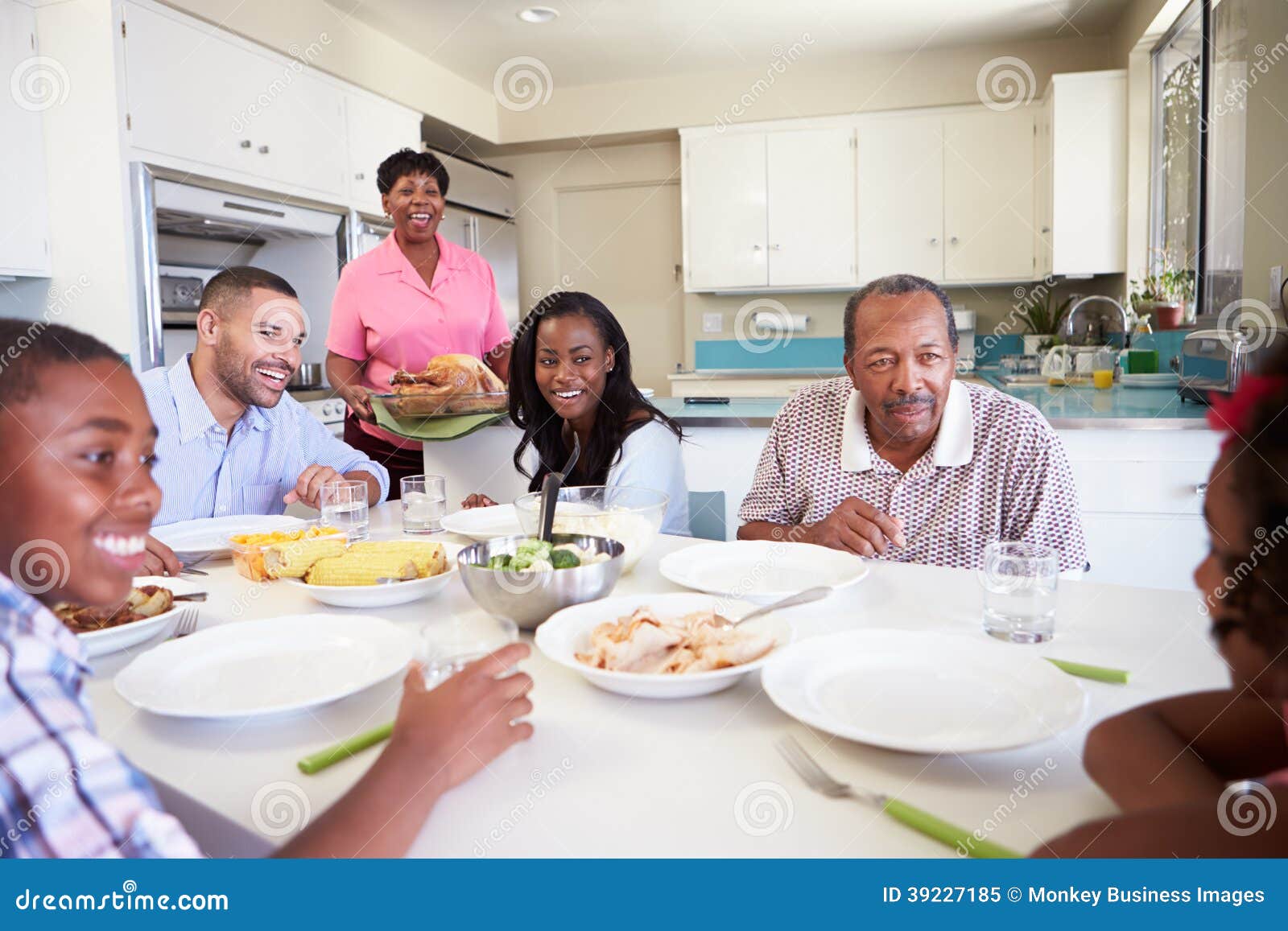 Multi-Generation Family Sitting Around Table Eating Meal Stock Image ...