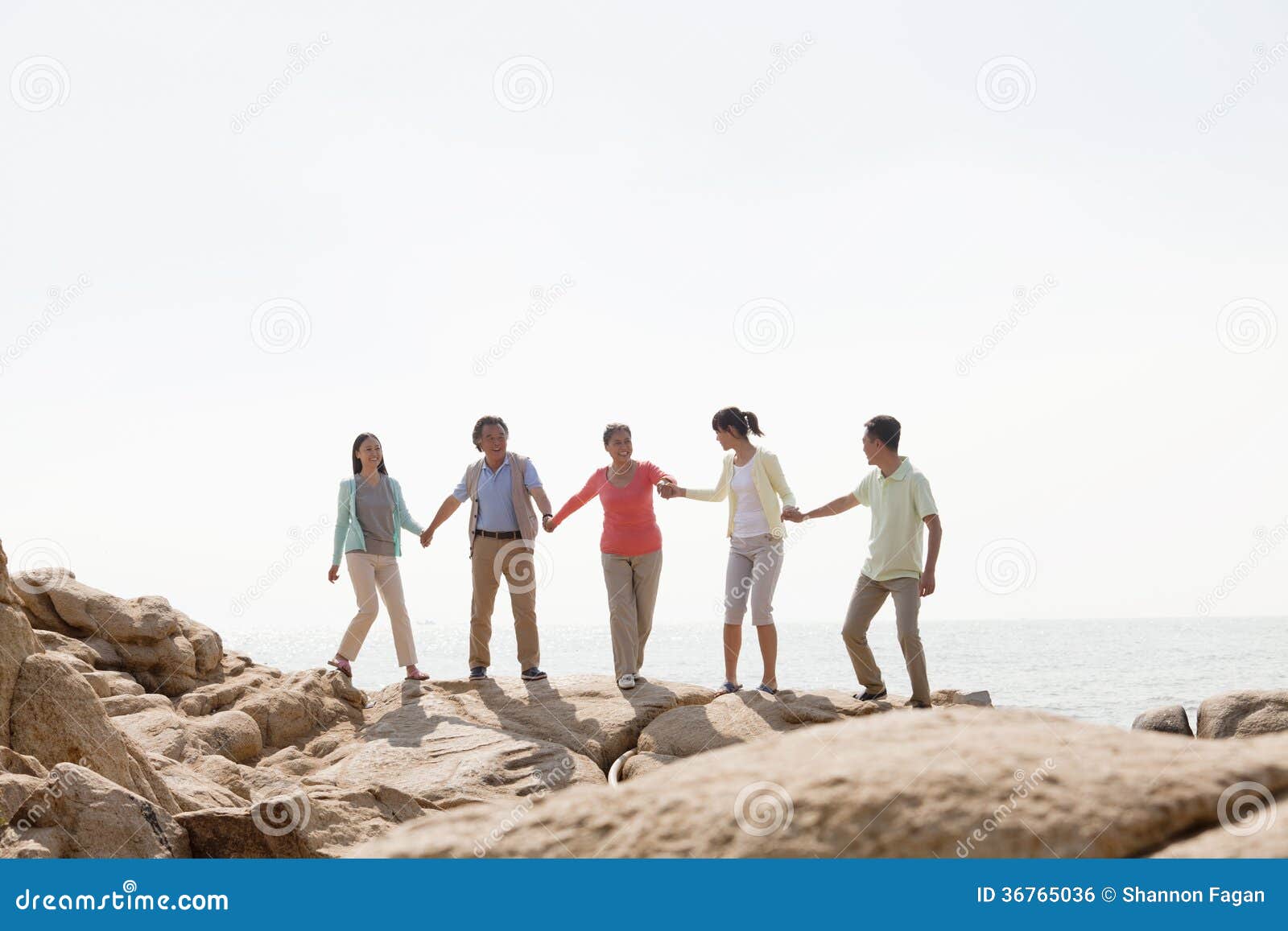 Multi-generational Family Holding Hands on Rocks by the Sea Stock Photo ...