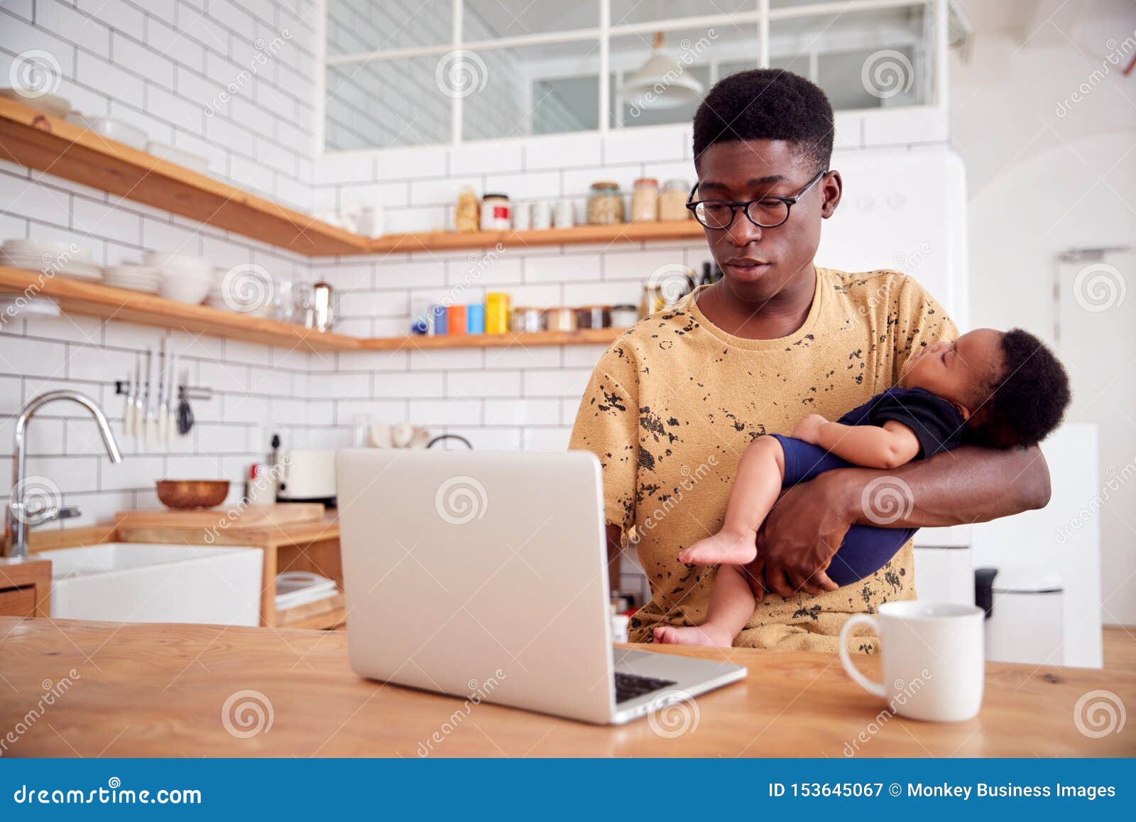Multi-Tasking Father Holds Sleeping Baby Son and Works on Laptop ...