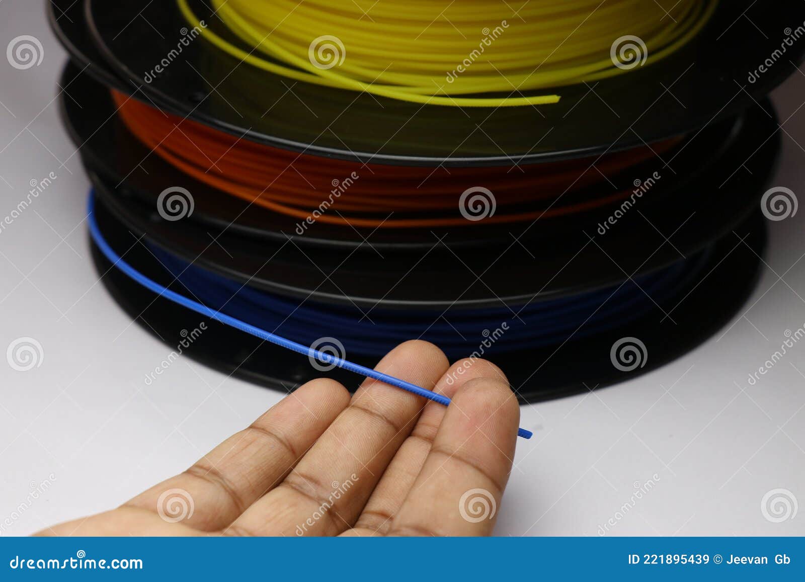 Multicolor Filament Spools or Reels Laid Flat with Hands Holding Blue ...