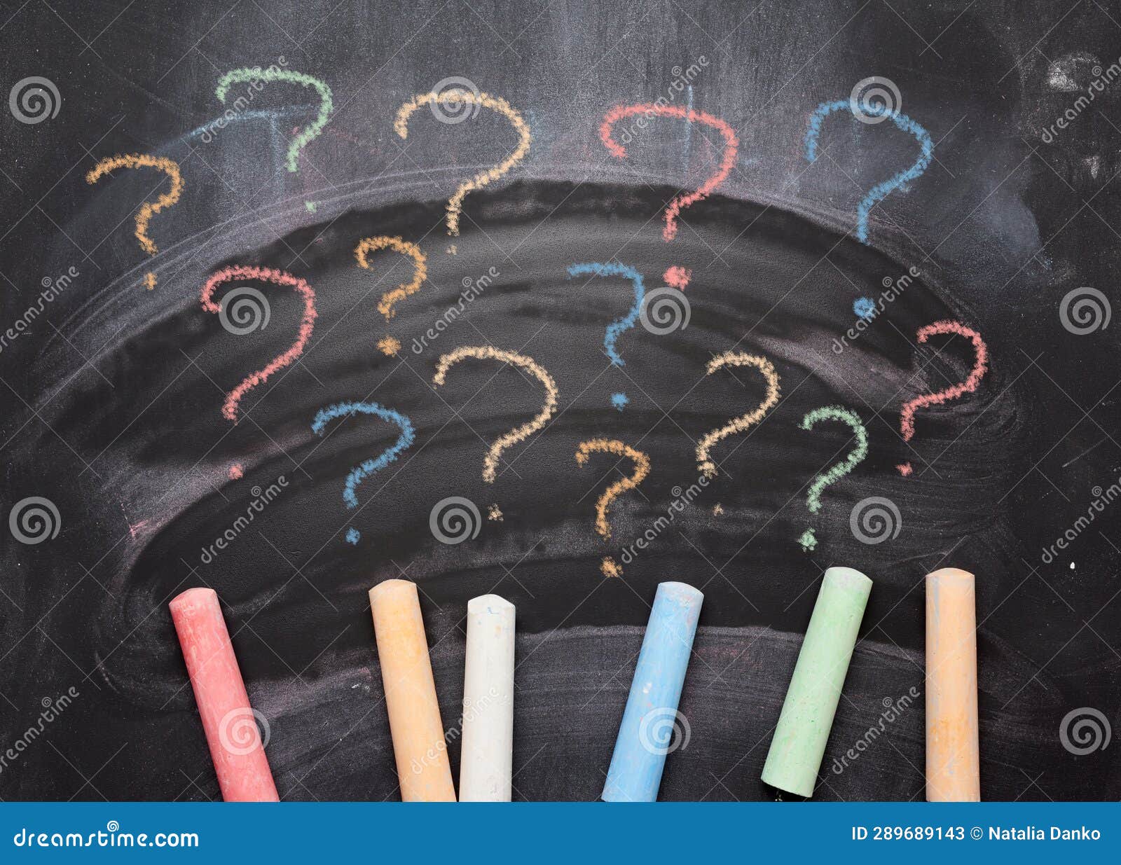 Multicolored Crayons on a Black Chalk Board and Drawn Question Marks ...