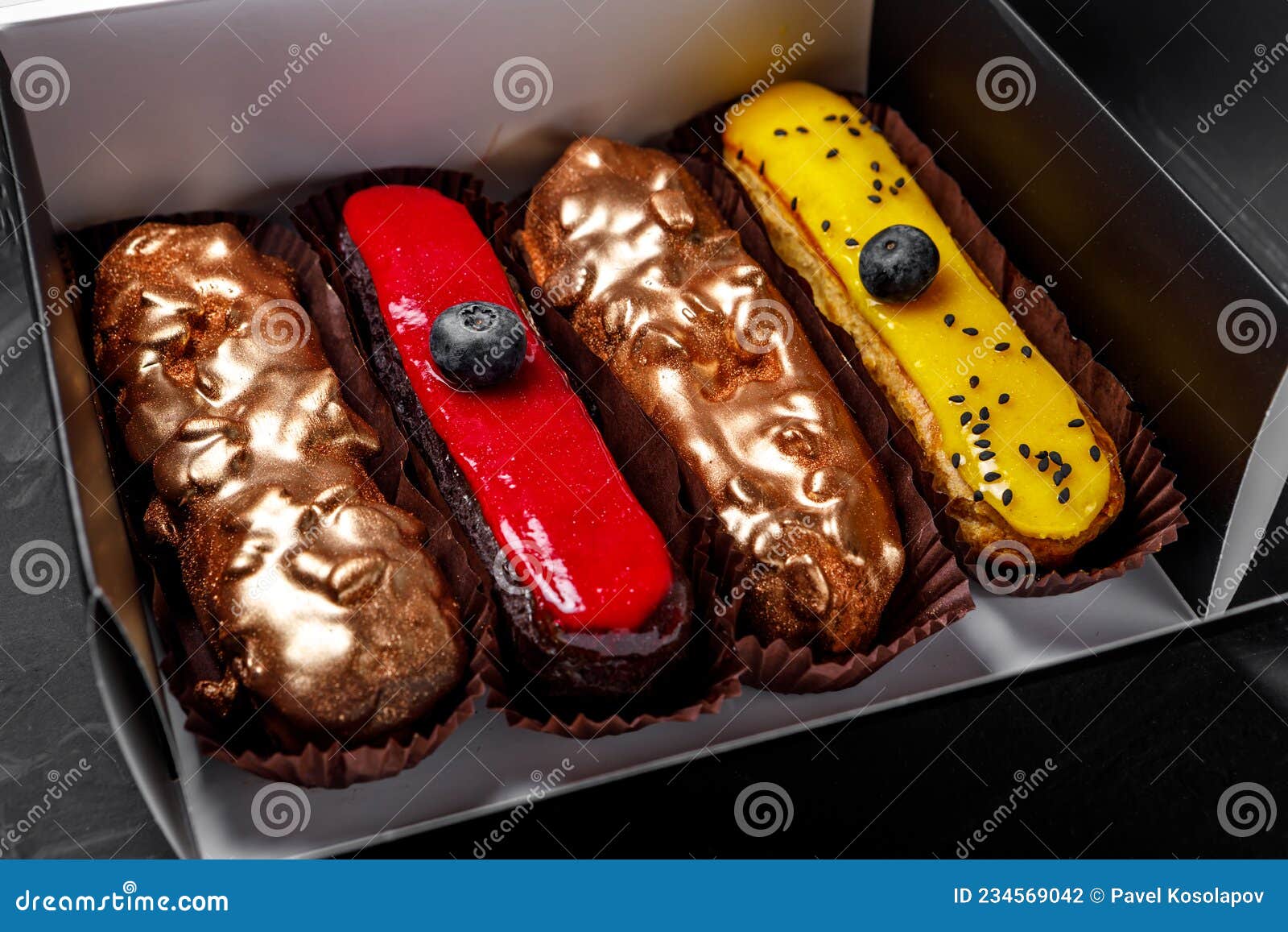 Multicolored Glazed Eclairs Decorated with Blueberries are in a ...