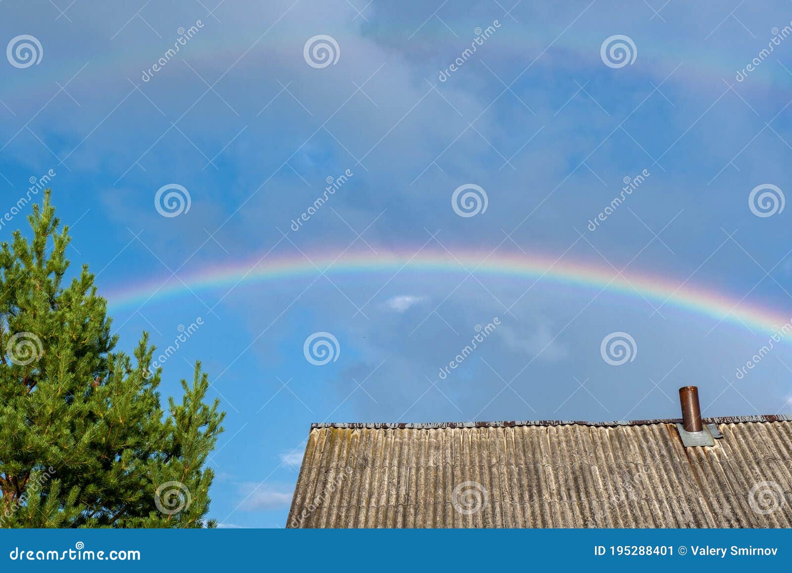 Multicolored Rainbow Over the Roof of the House Against the Blue Sky ...