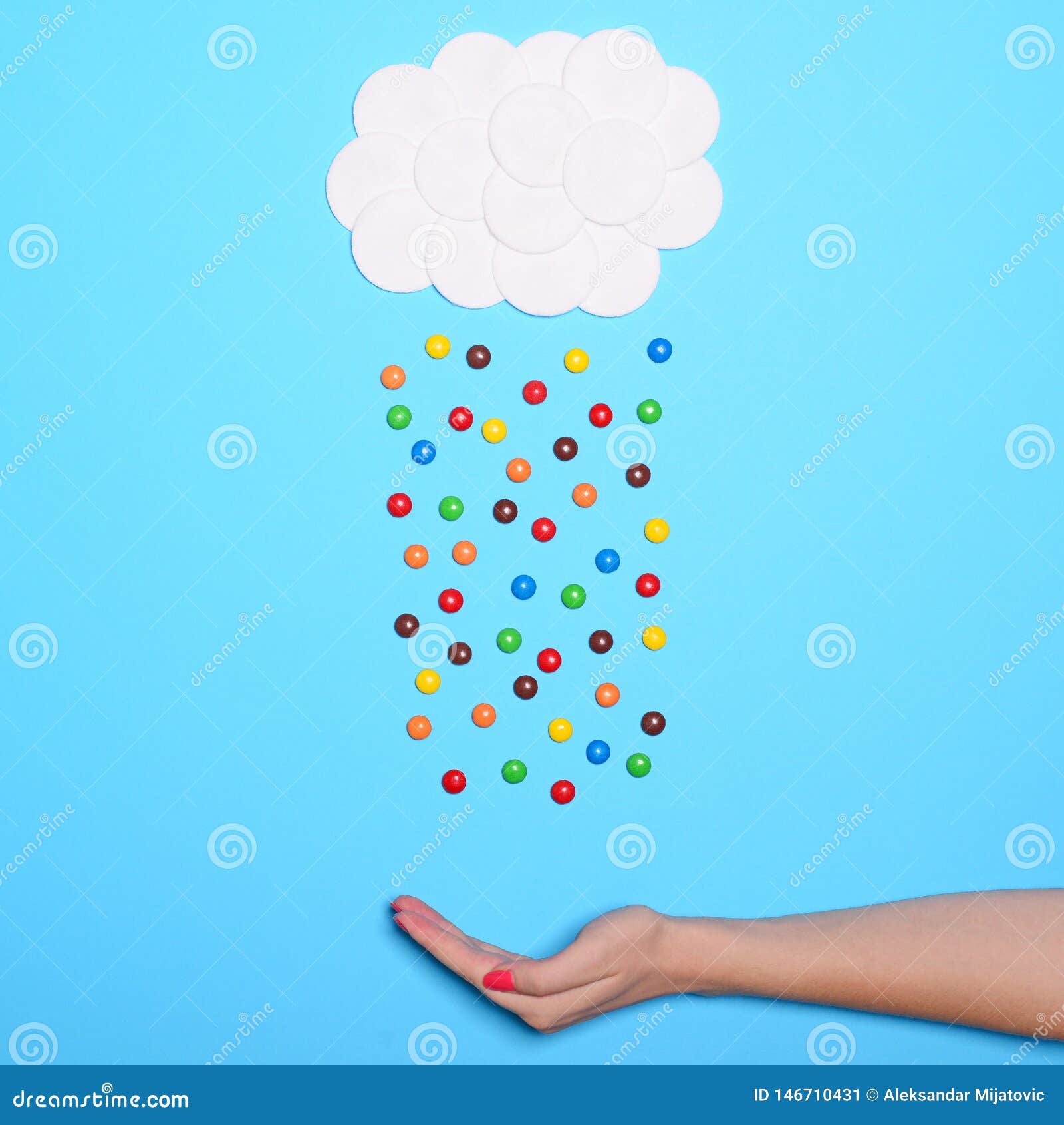 Multicolored Sweets Raining from Cotton Clouds in Hand Against Blue ...
