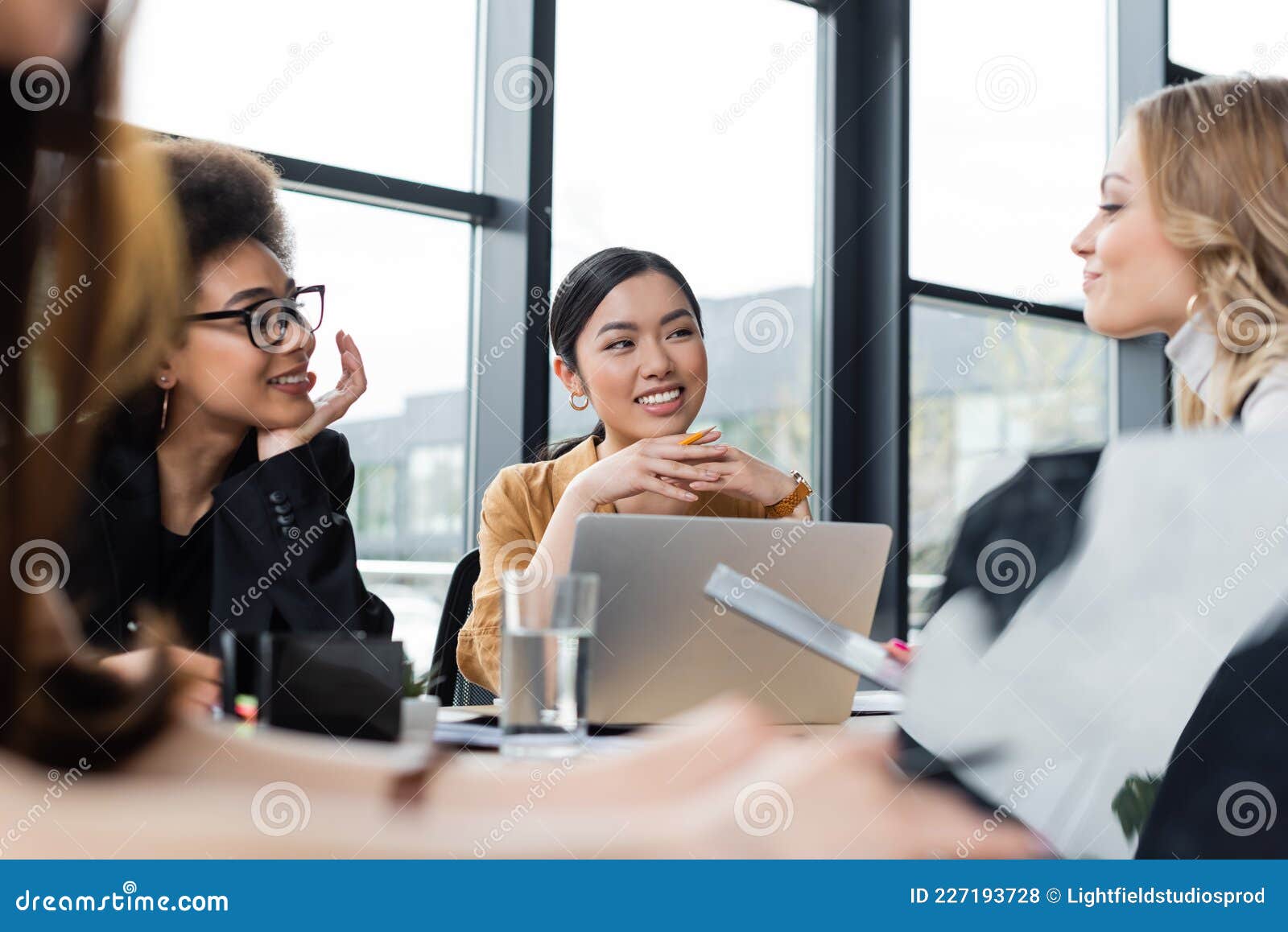 Multicultural Businesswomen Talking Near Laptops on Stock Photo - Image ...