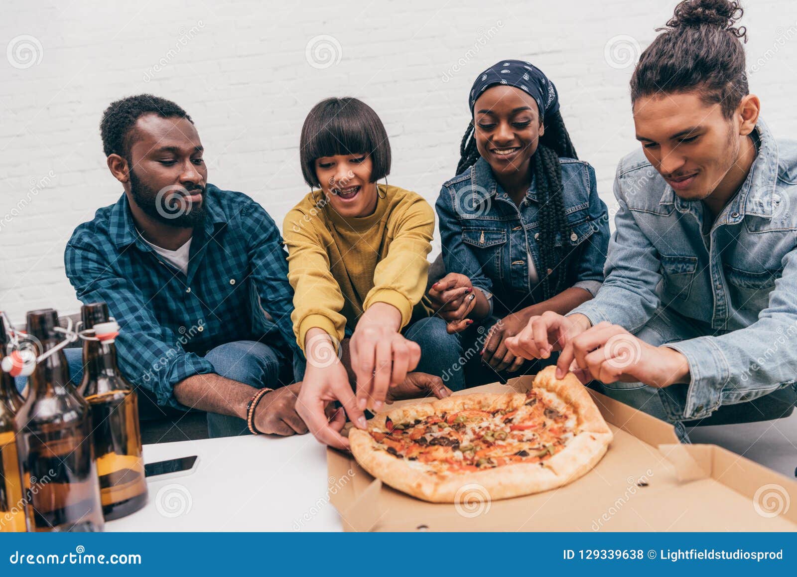 Multicultural Friends Eating Pizza at Table with Bottles of Stock Photo ...