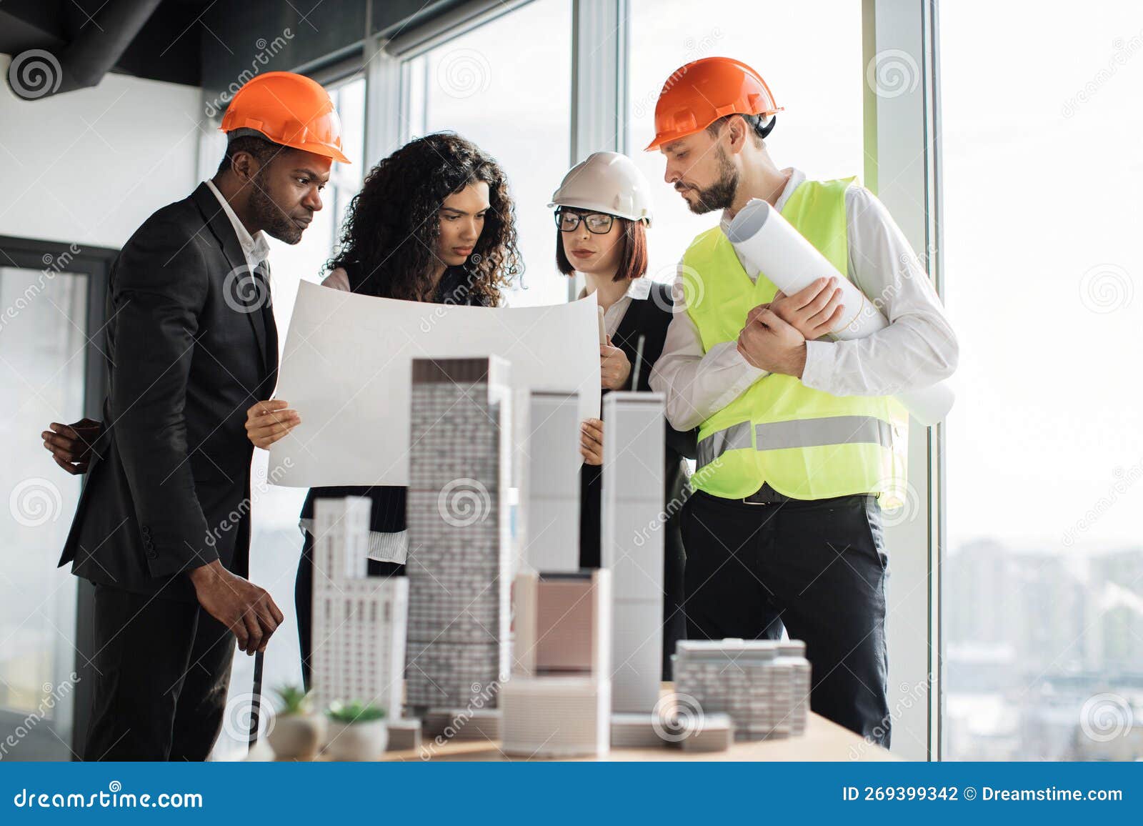 Multicultural Workers in Reflective Vest and Helmets with Blueprint ...