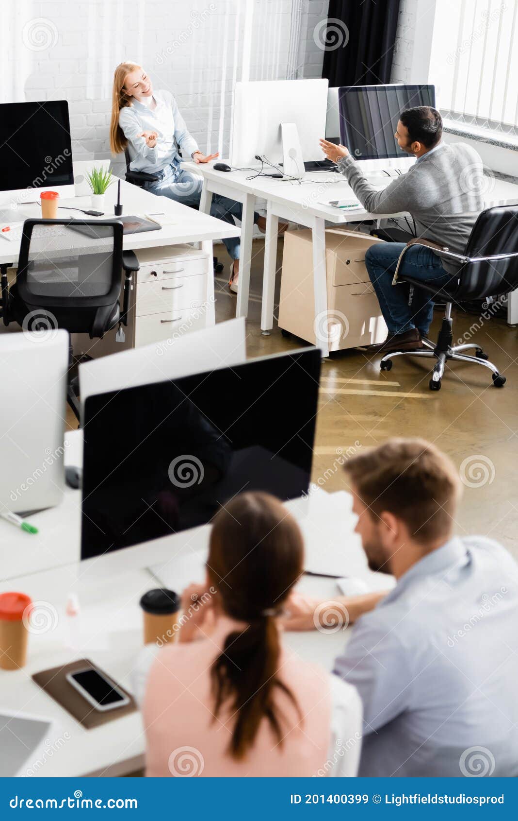 Multiethnic Businesspeople Talking while Using Computers Stock Image ...