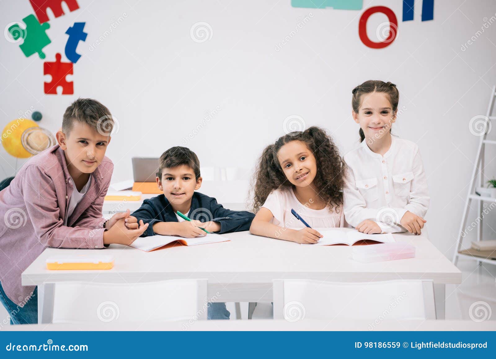 Multiethnic Students Sitting Together at Desk and Smiling at Camera in ...