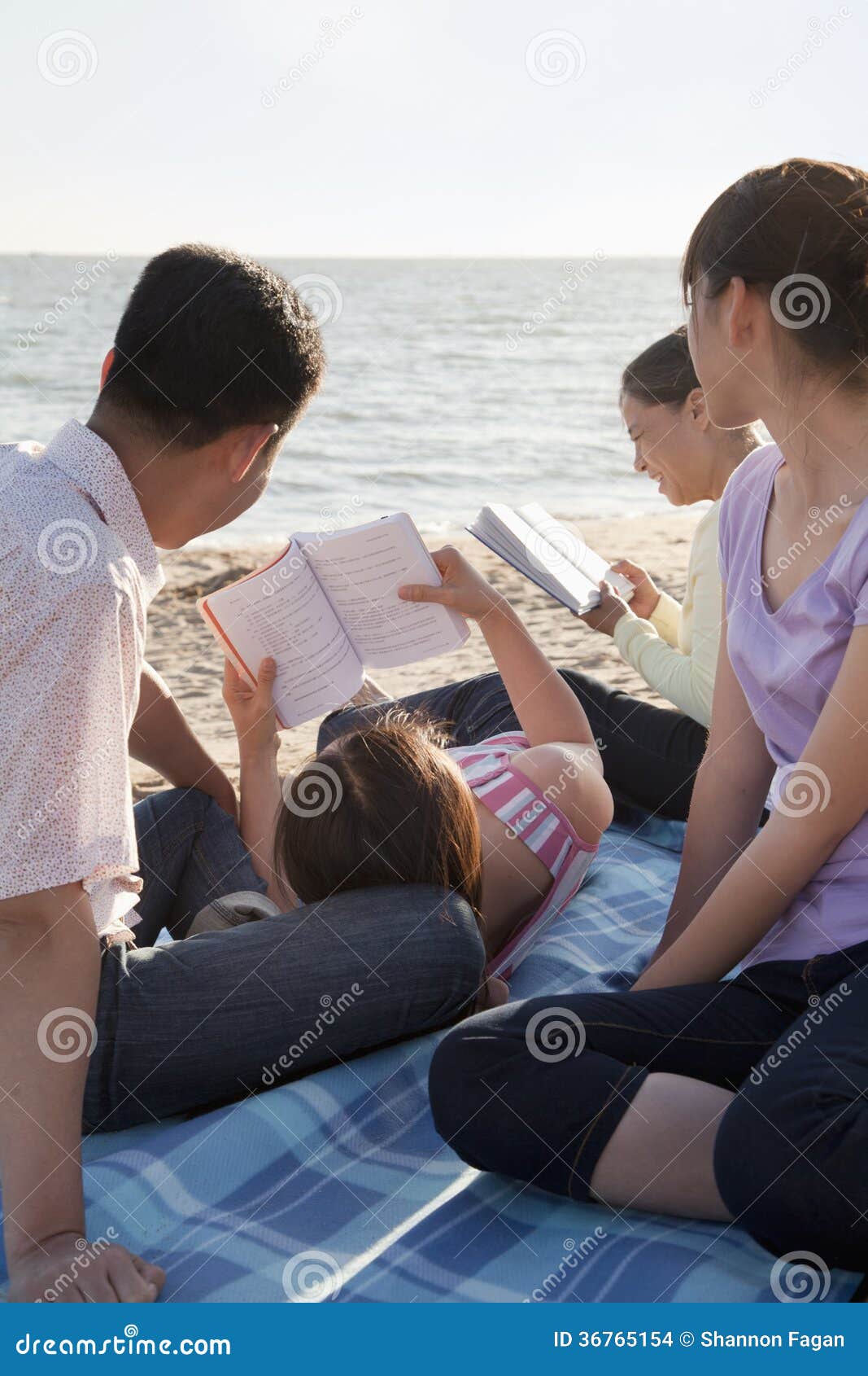 Multigenerational Family Relaxing and Reading on the Beach Stock Photo ...
