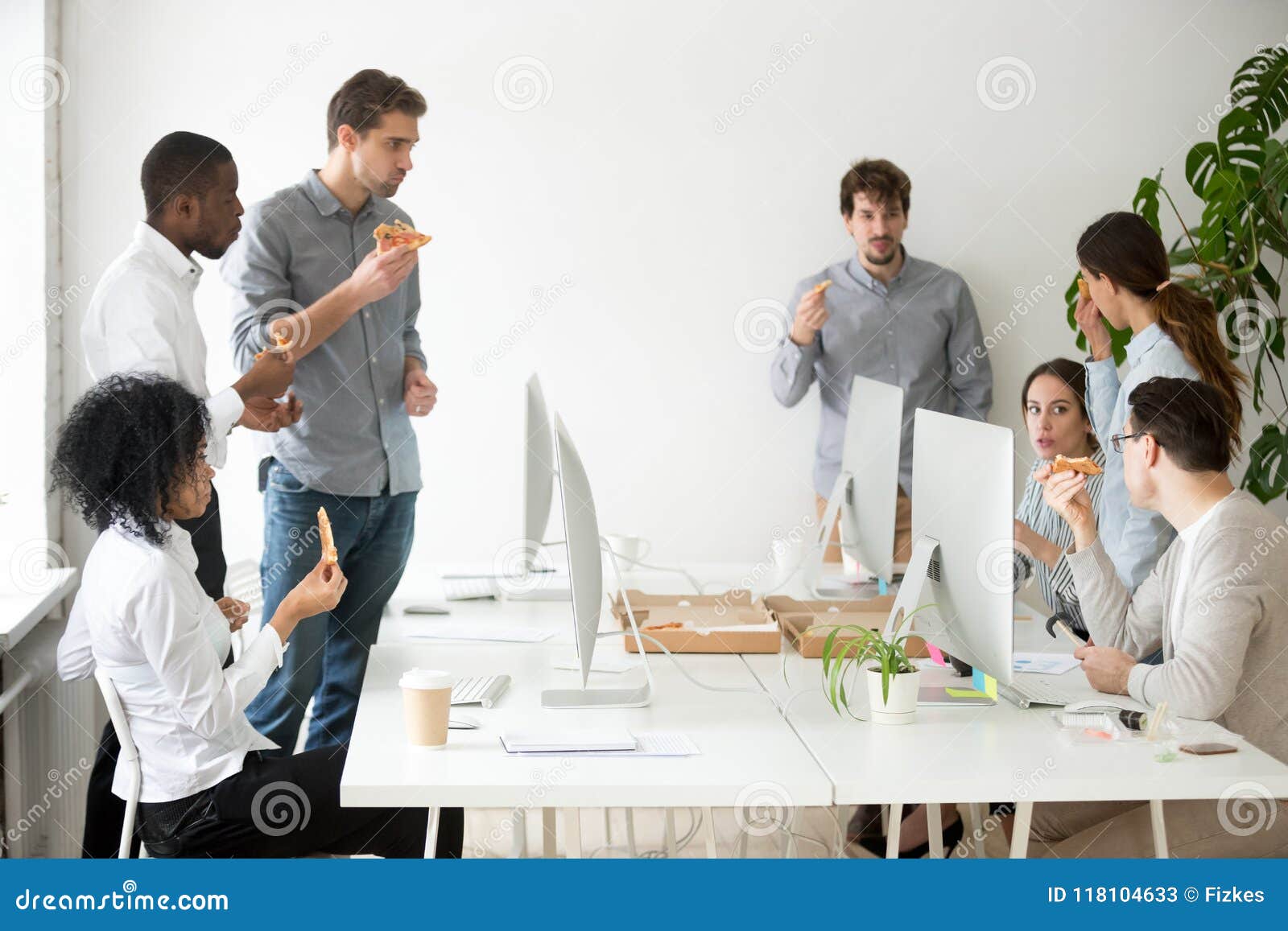 Multinational Work Group Talking and Eating Pizza at Workplace Stock ...