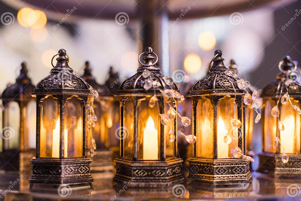 Multiple Candles Illuminate Rows of Lamps on a Table. Stock Image ...