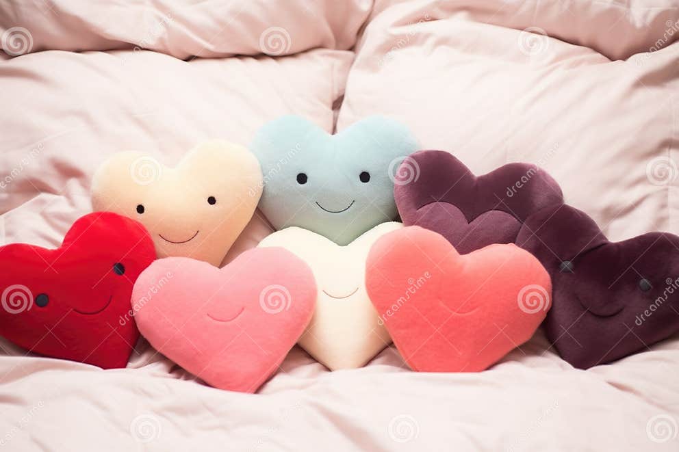 Multiple Heart-shaped Soft Plushies in Different Colors on a Bed Stock ...