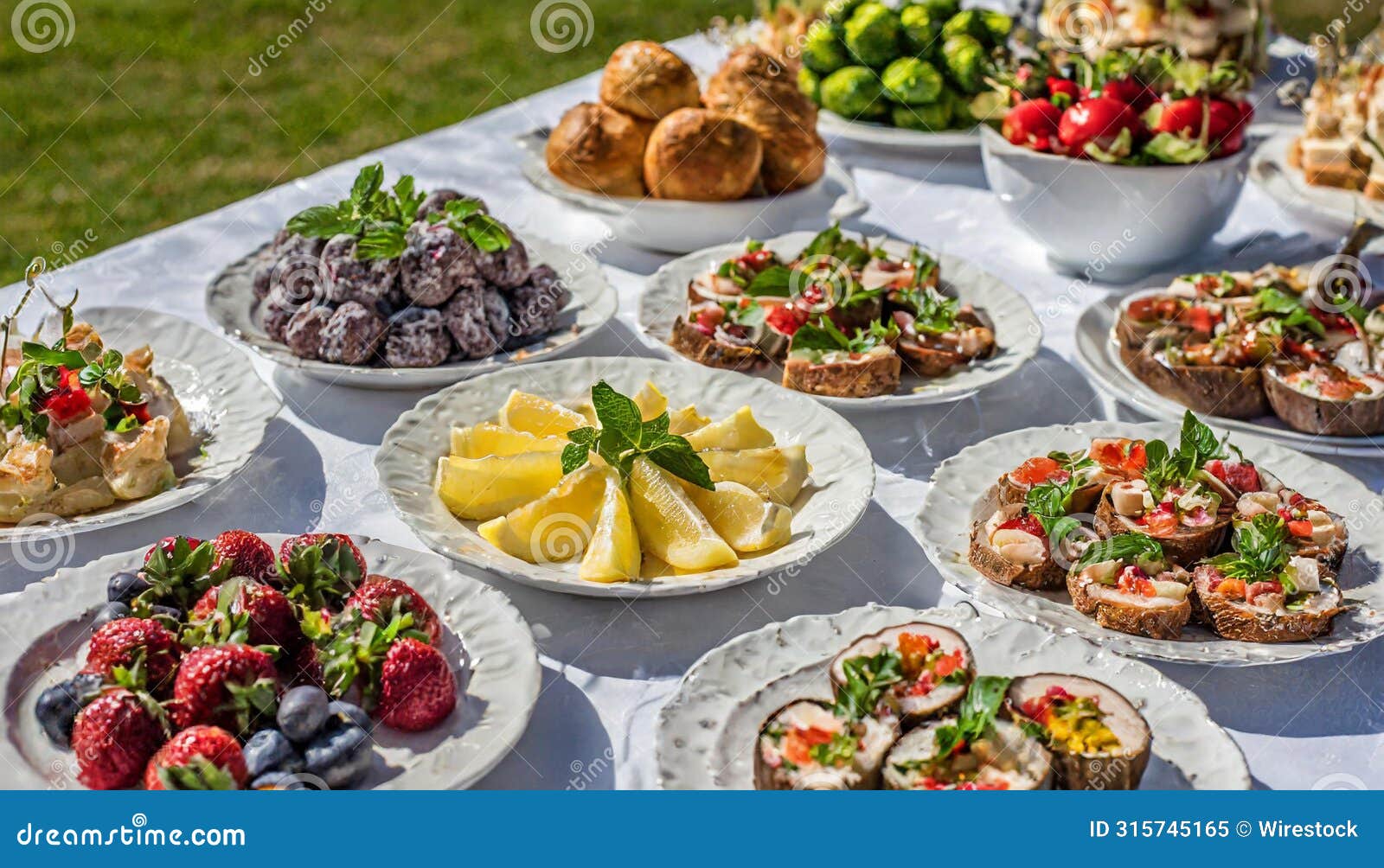 Multiple Plates of Various Dishes on a White Outdoor Table with Fresh ...